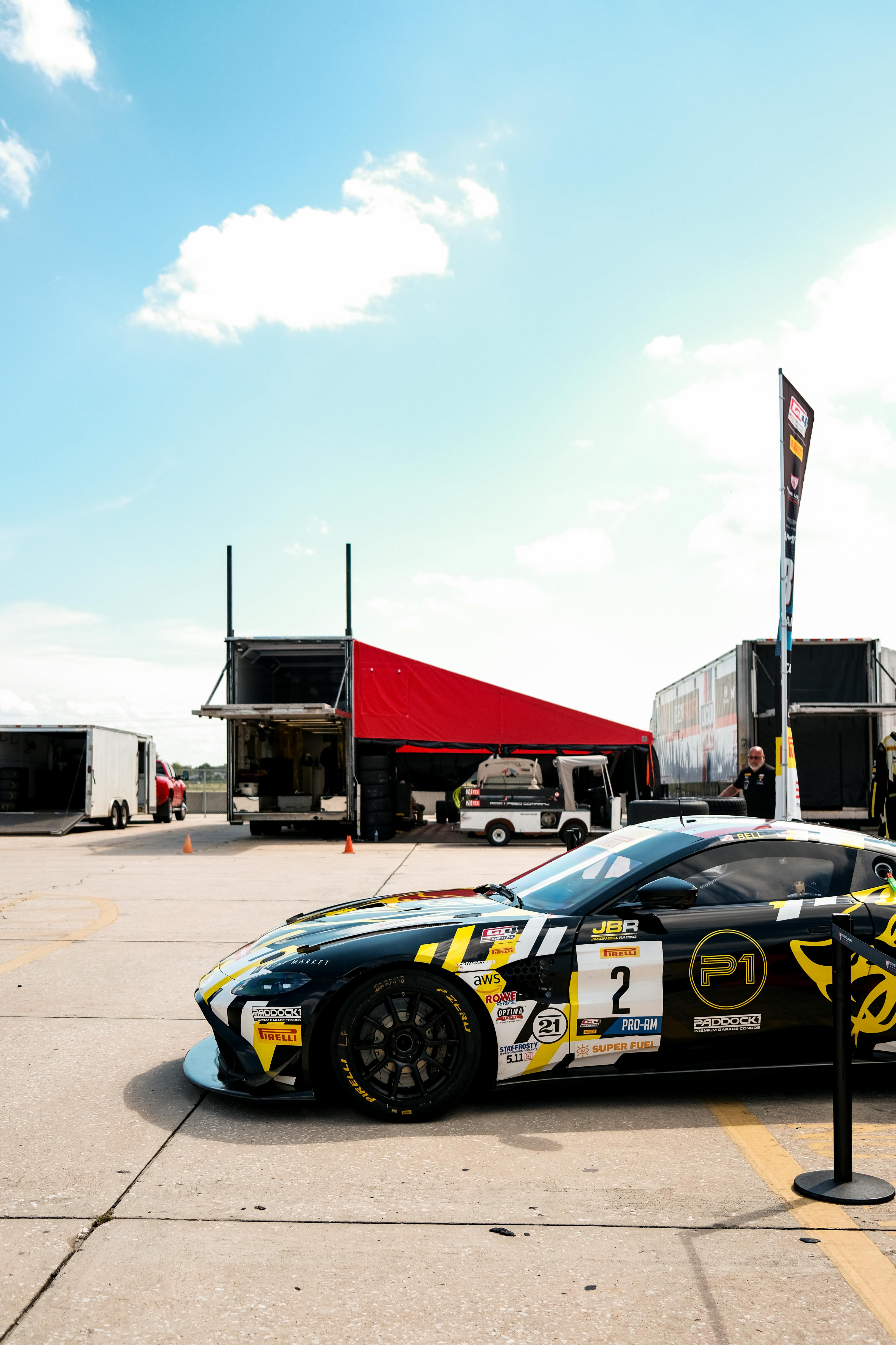 A black and yellow racing car parked in front of a building · Free ...