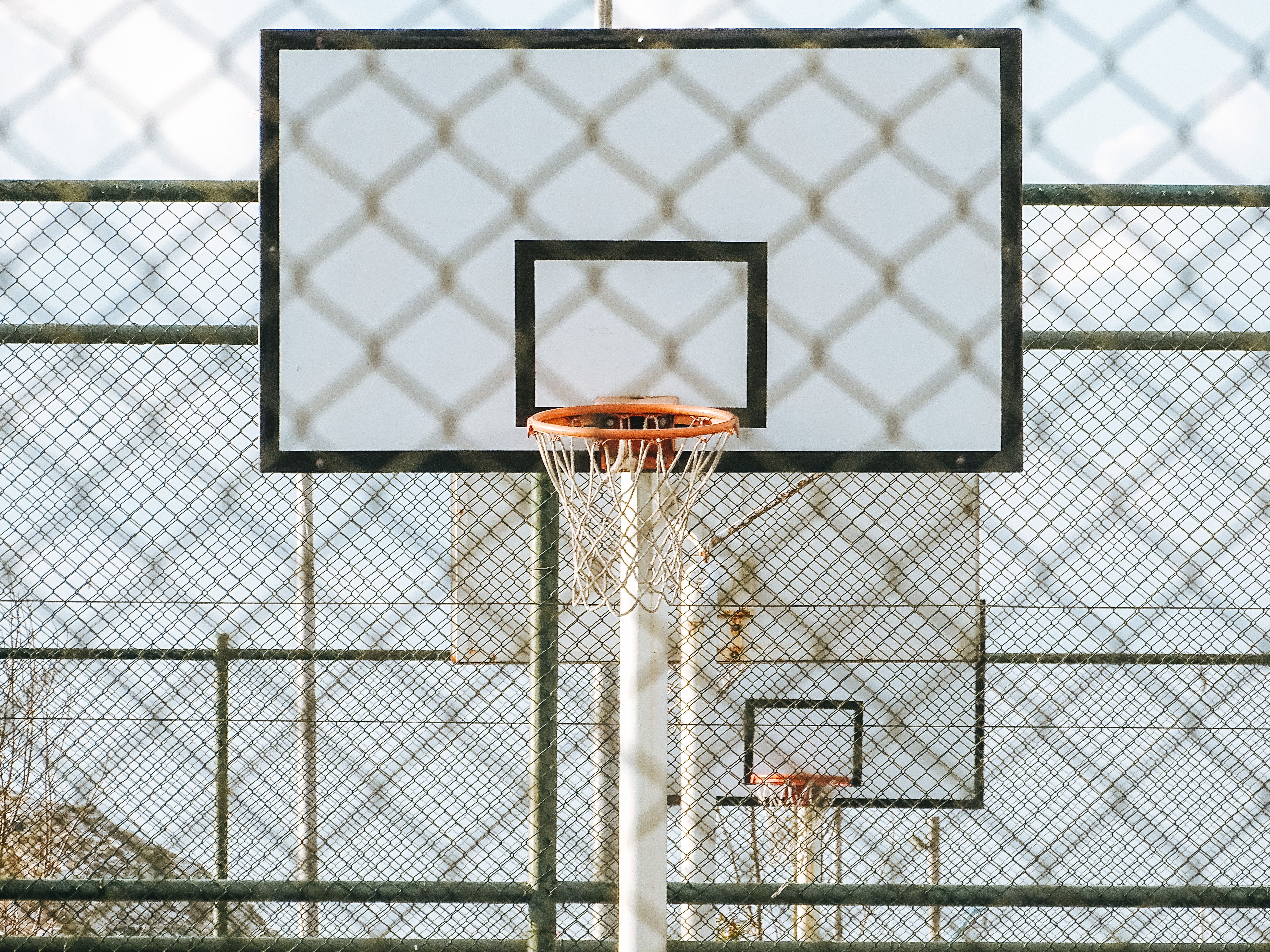 Basketball Baskets Behind a Chainlink Fence · Free Stock Photo