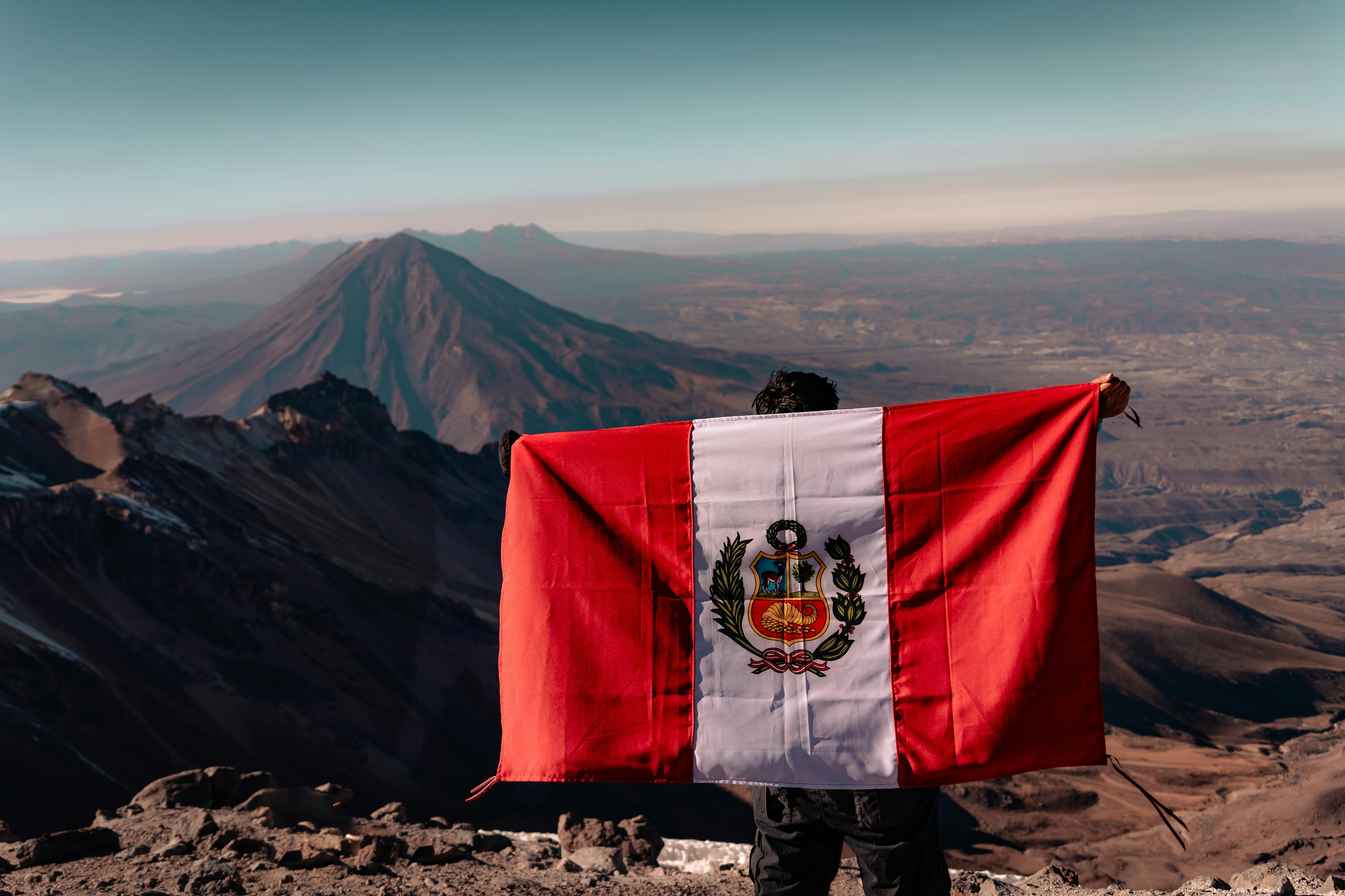 Person Holding a Peru Flag on Top of a Mountain · Free Stock Photo