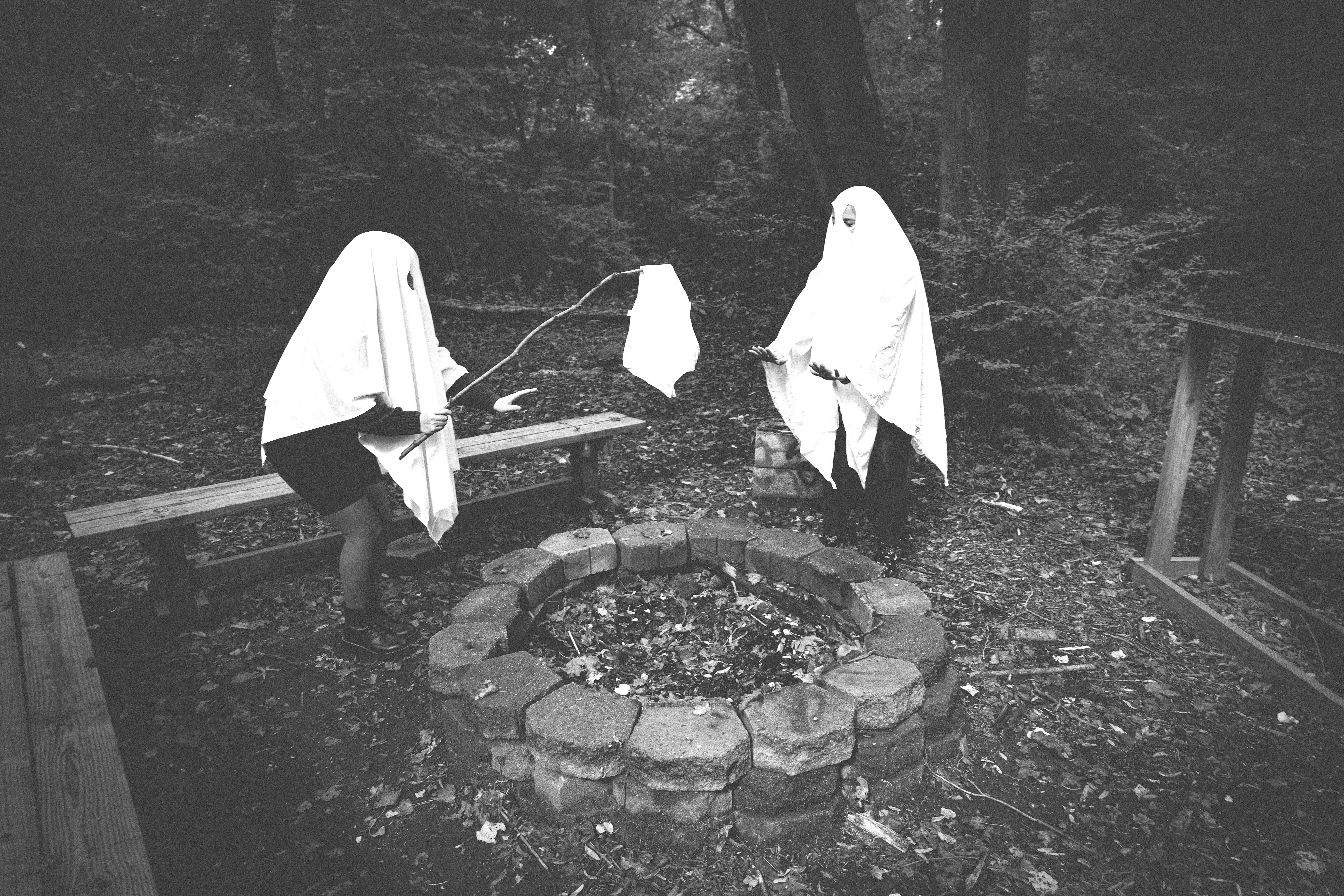 Two people in white robes sitting around a fire pit · Free Stock Photo
