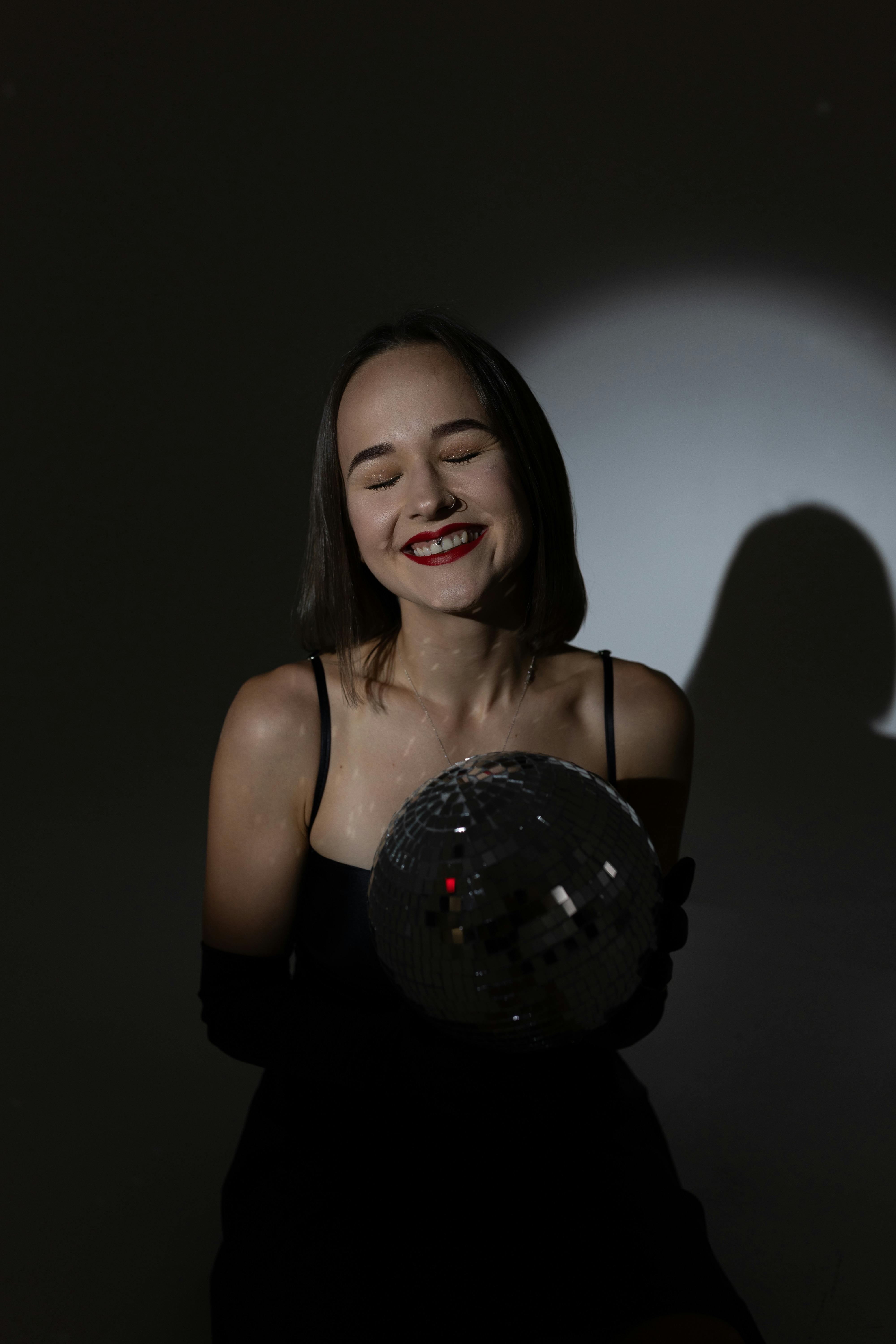 Smiling Woman in Black Dress Standing in Spotlight Holding Disco Ball ...