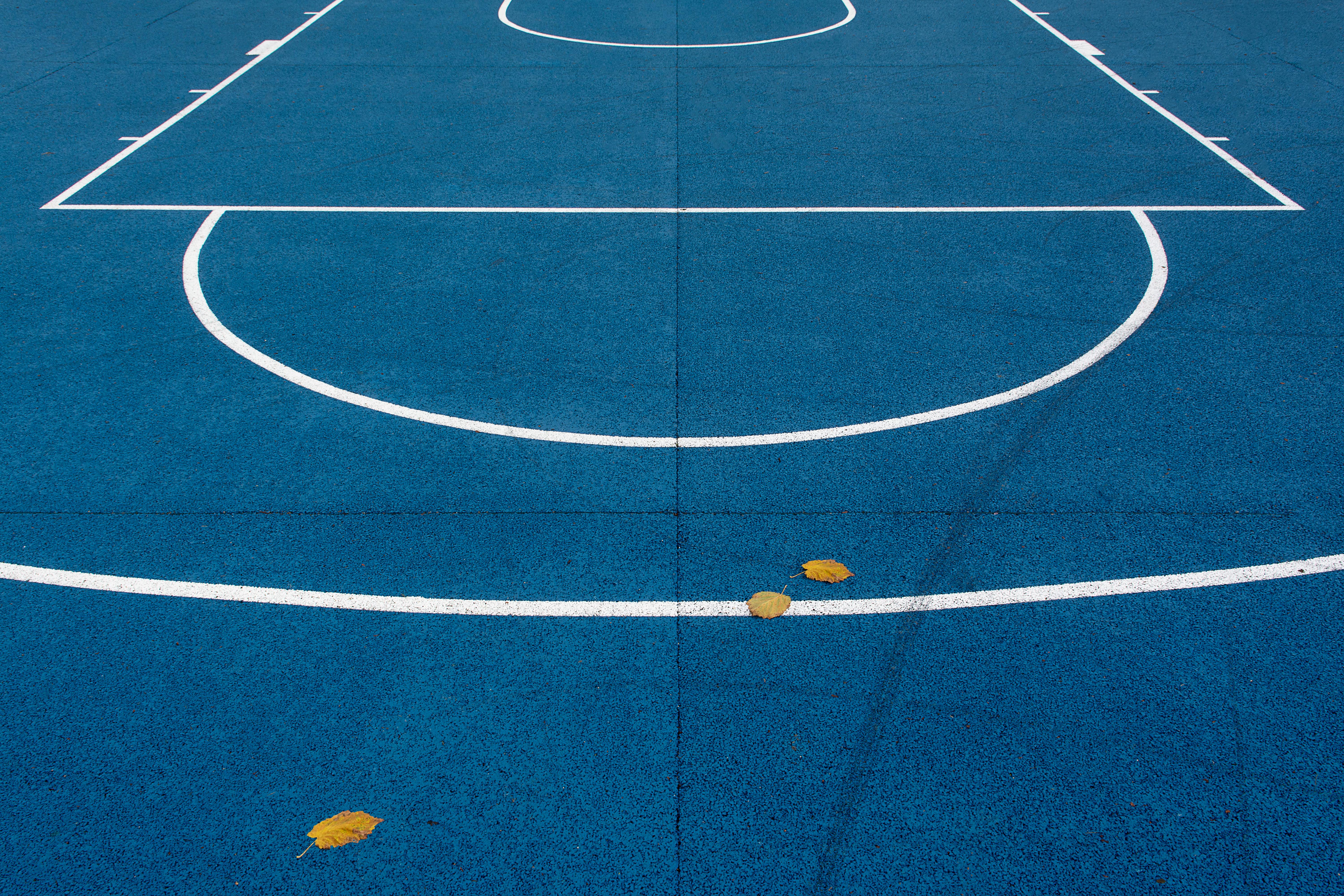 Autumn Leaves on a Blue Basketball Court · Free Stock Photo