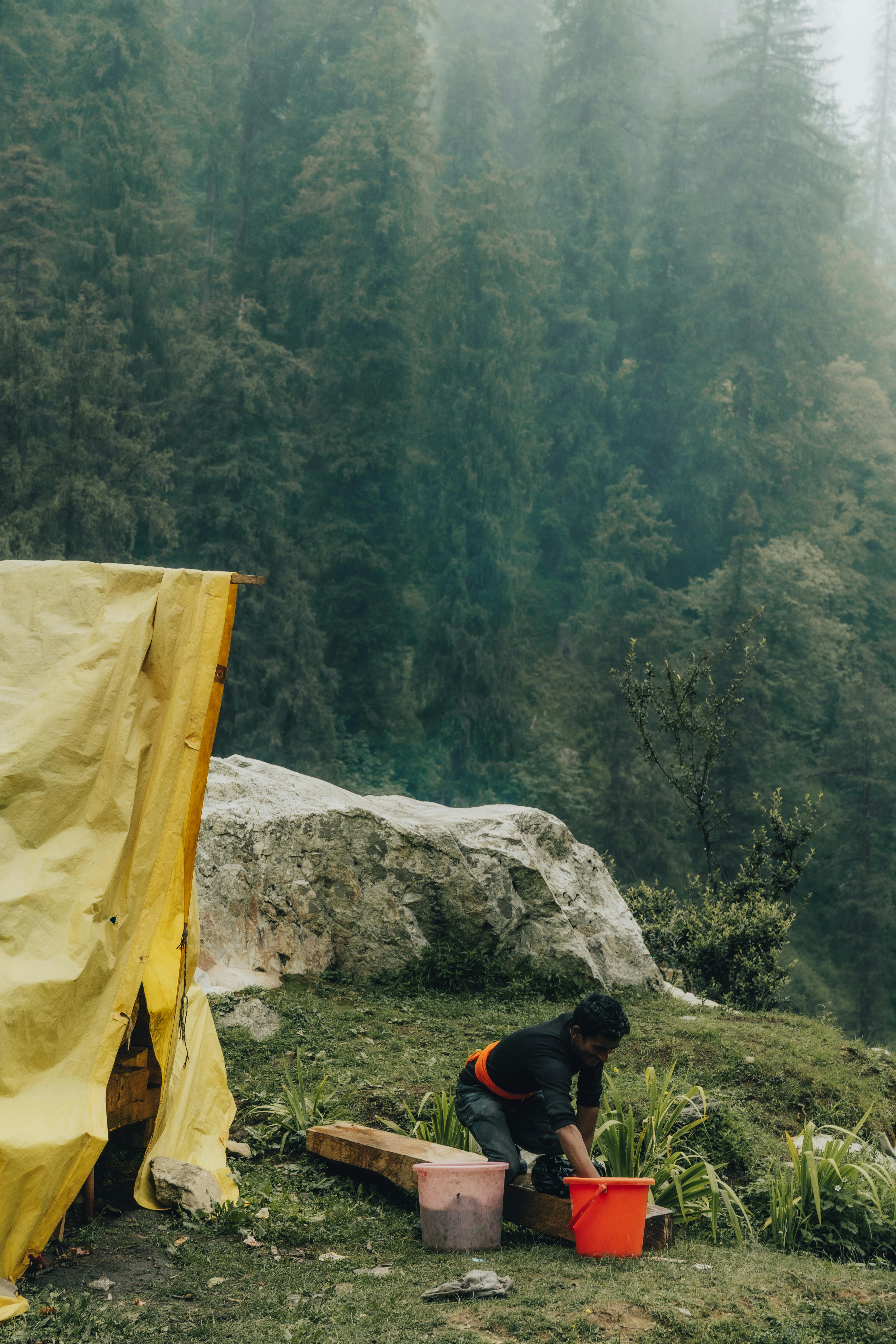 Man Sitting with Buckets at Camping · Free Stock Photo