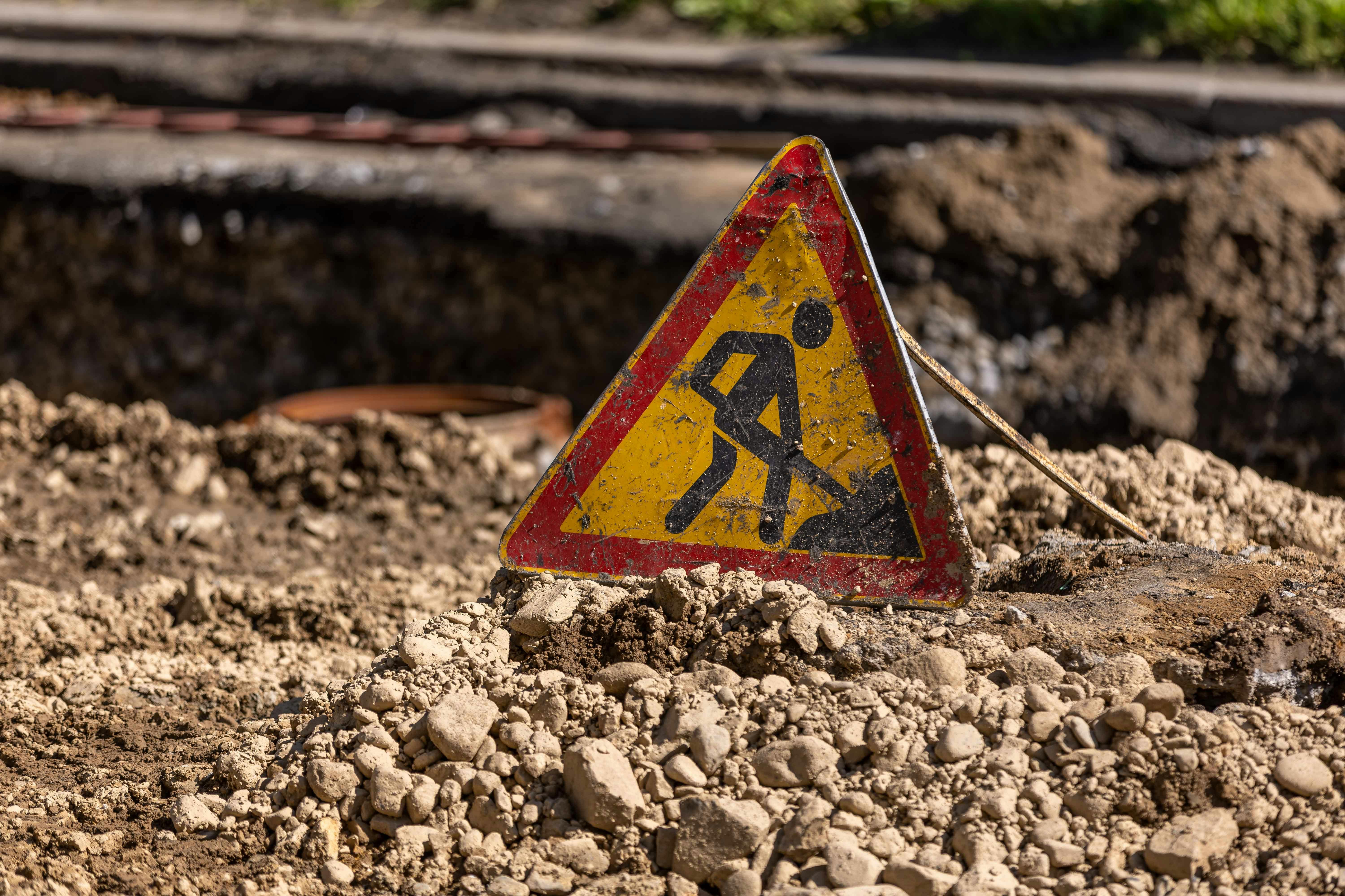 A Dirty Roadworks Sign Standing on a Pile of Dirt · Free Stock Photo