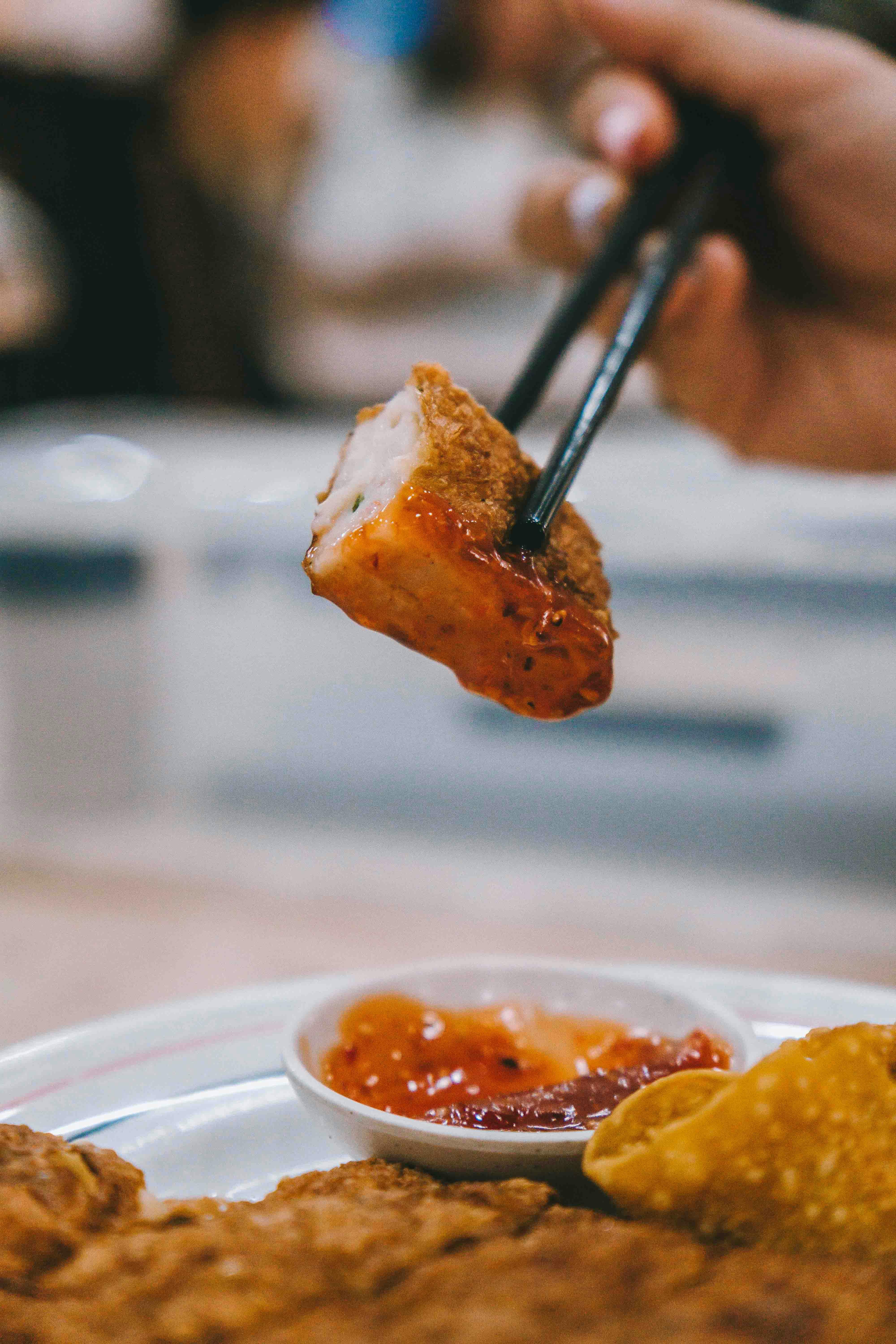 Close-up of a Person Holding a Crispy Piece of Food with Chopsticks ...