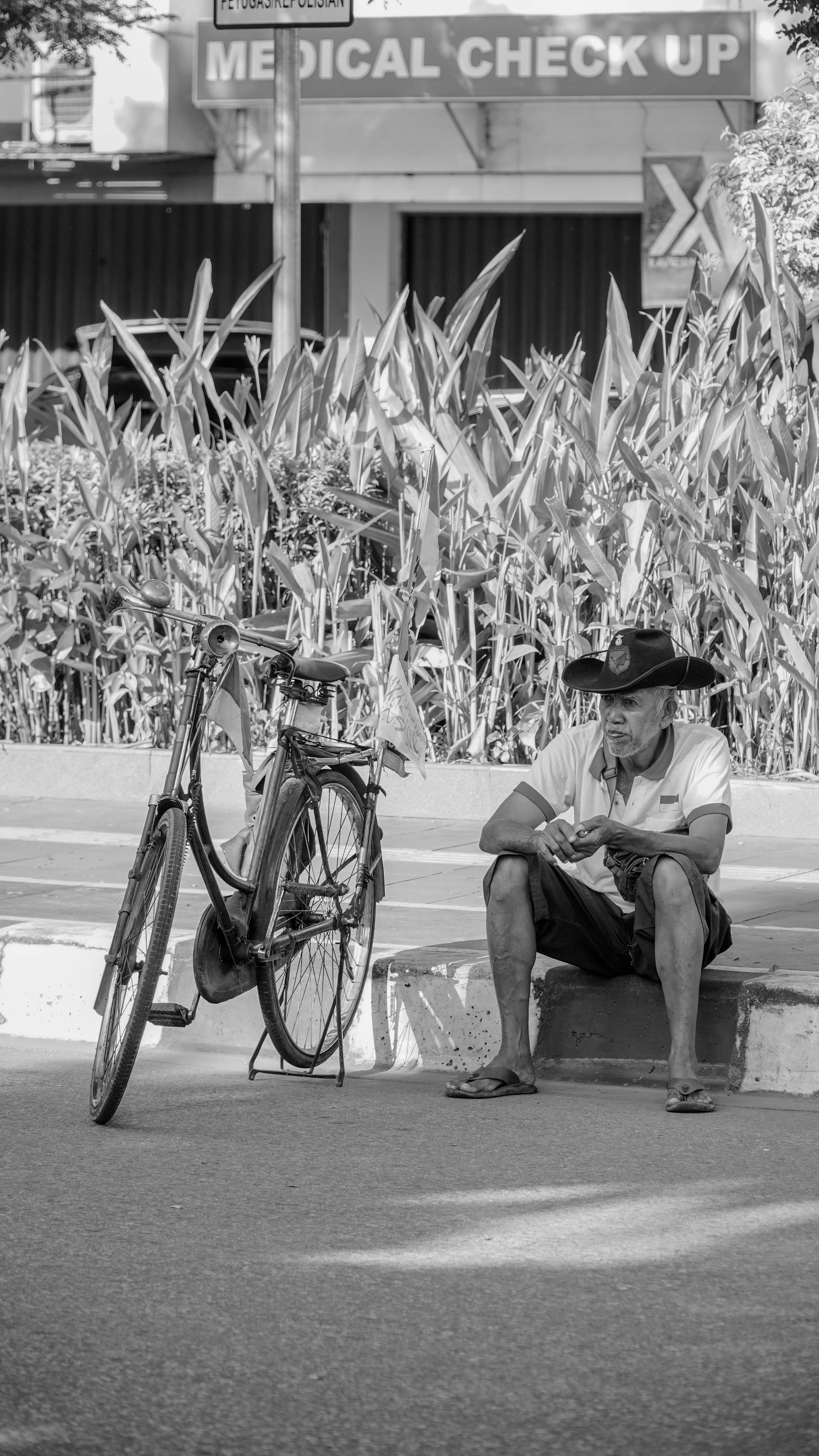 A man sitting on the curb with a bicycle · Free Stock Photo