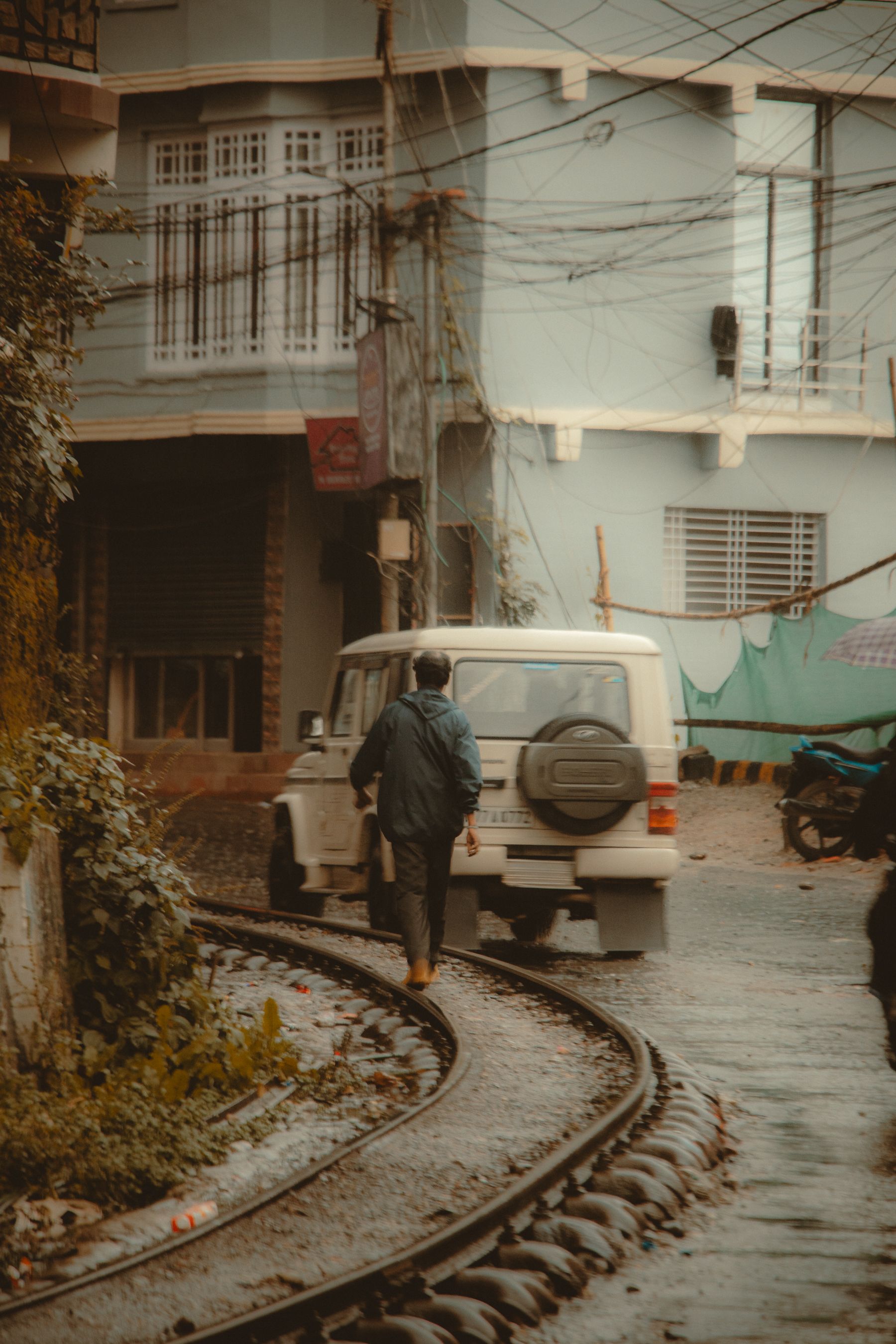 Passerby Walking on the Narrow-Gauge Railway Tracks and a White SUV ...
