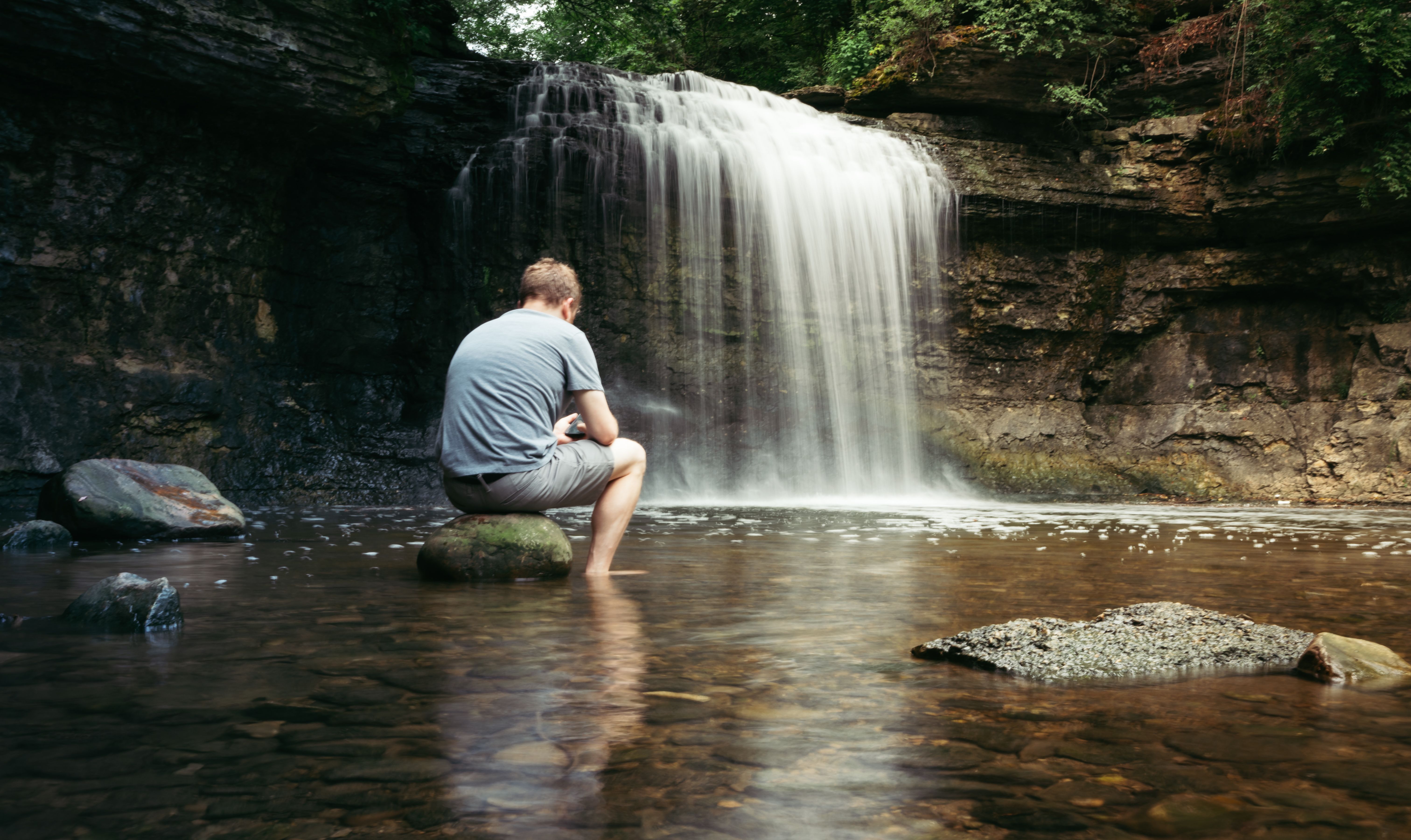 Man Sitting near Waterfall · Free Stock Photo