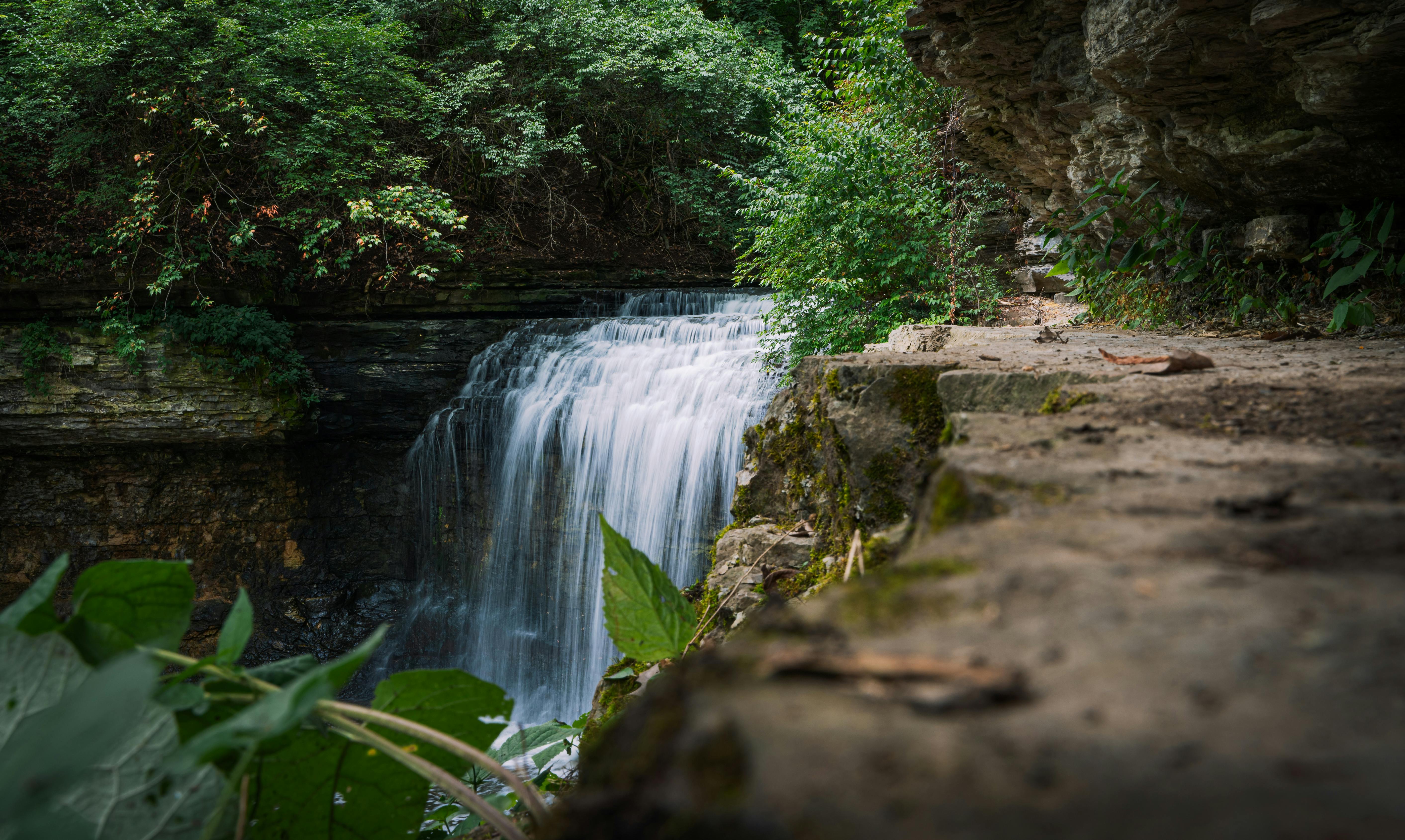 A waterfall is flowing down a rocky path · Free Stock Photo