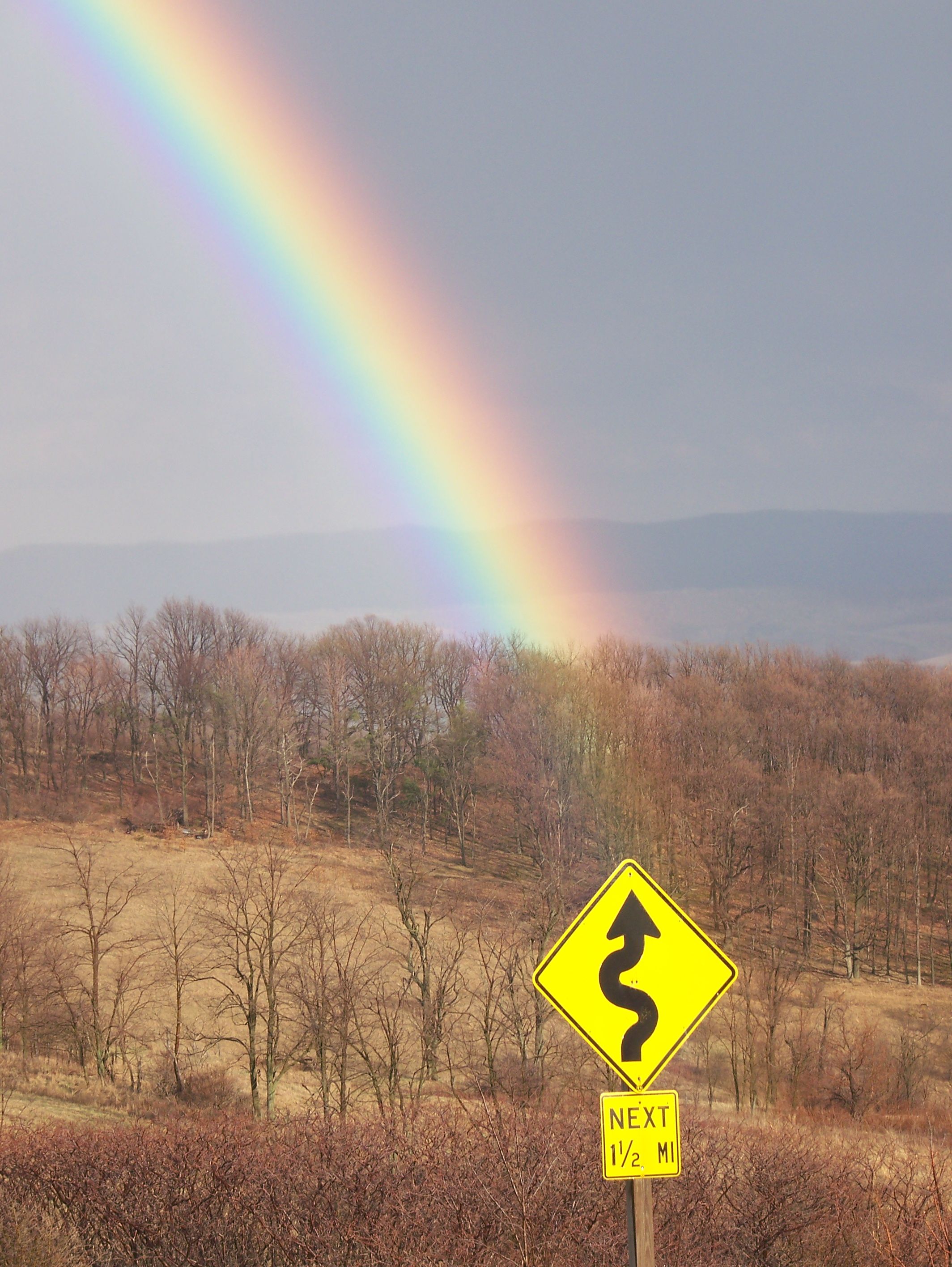 Rainbow Ending Near Road with Traffic Sign · Free Stock Photo