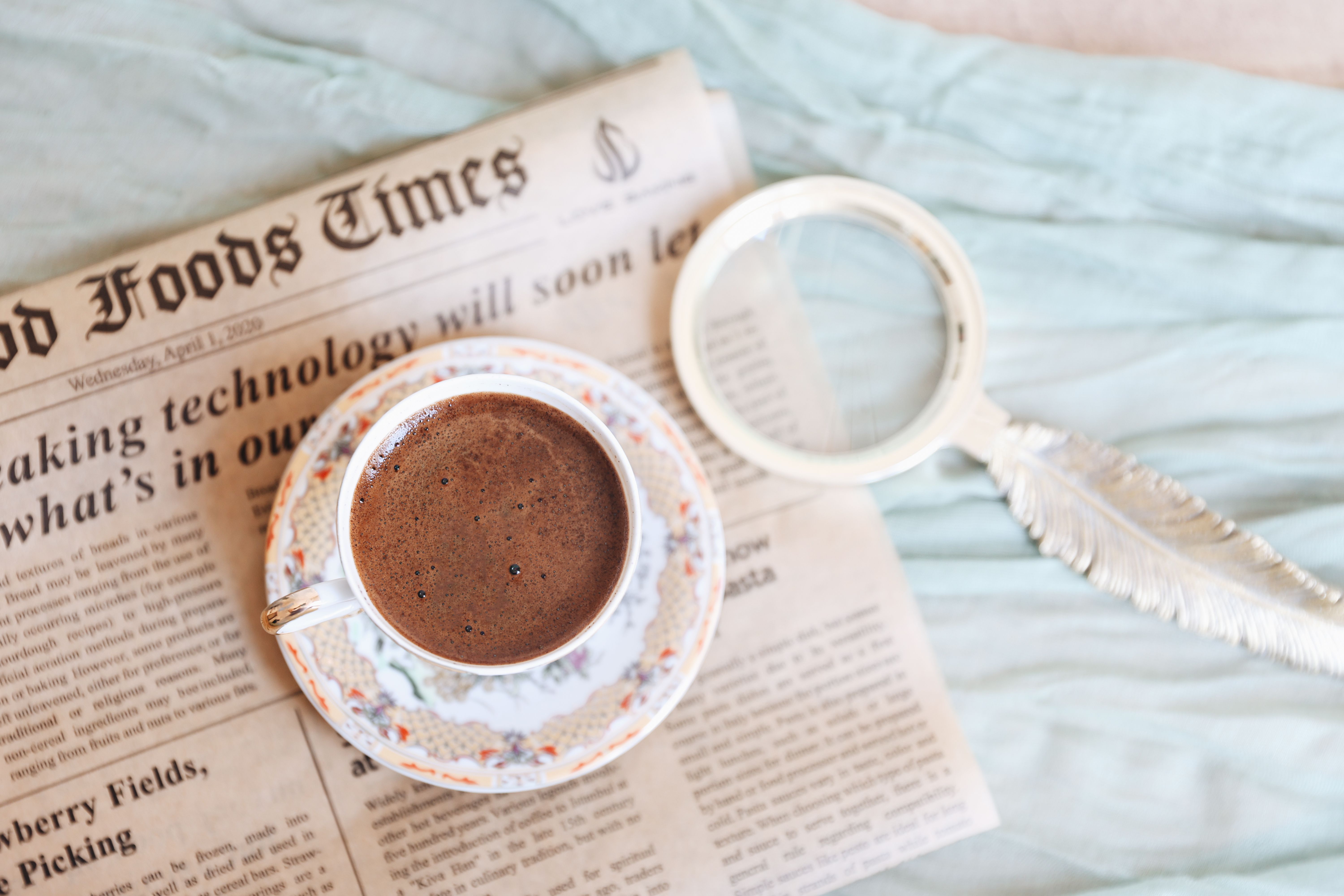 Cup of Coffee and Saucer on a Newspaper Next to a Magnifying Glass ...