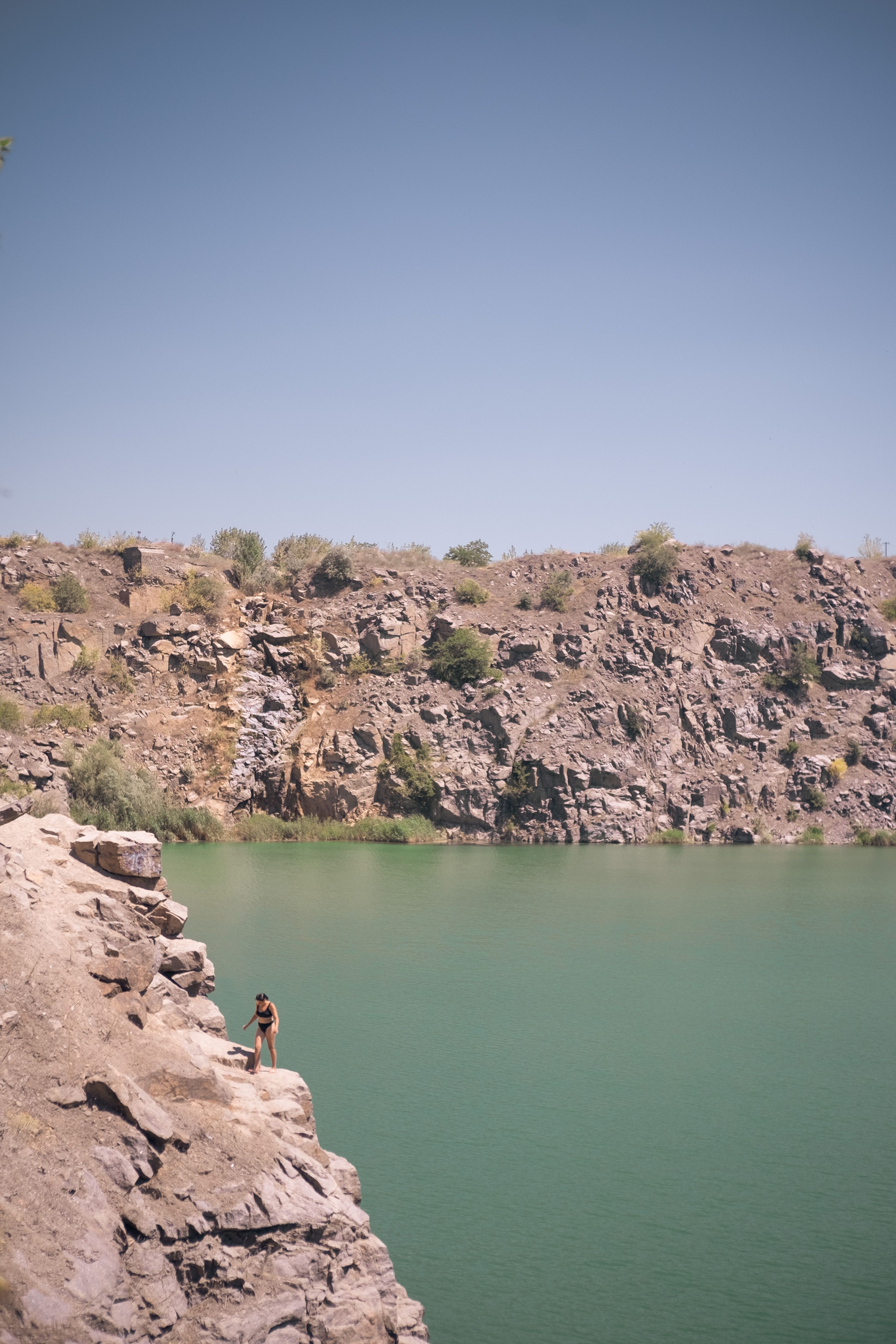 A person standing on a cliff overlooking a lake · Free Stock Photo