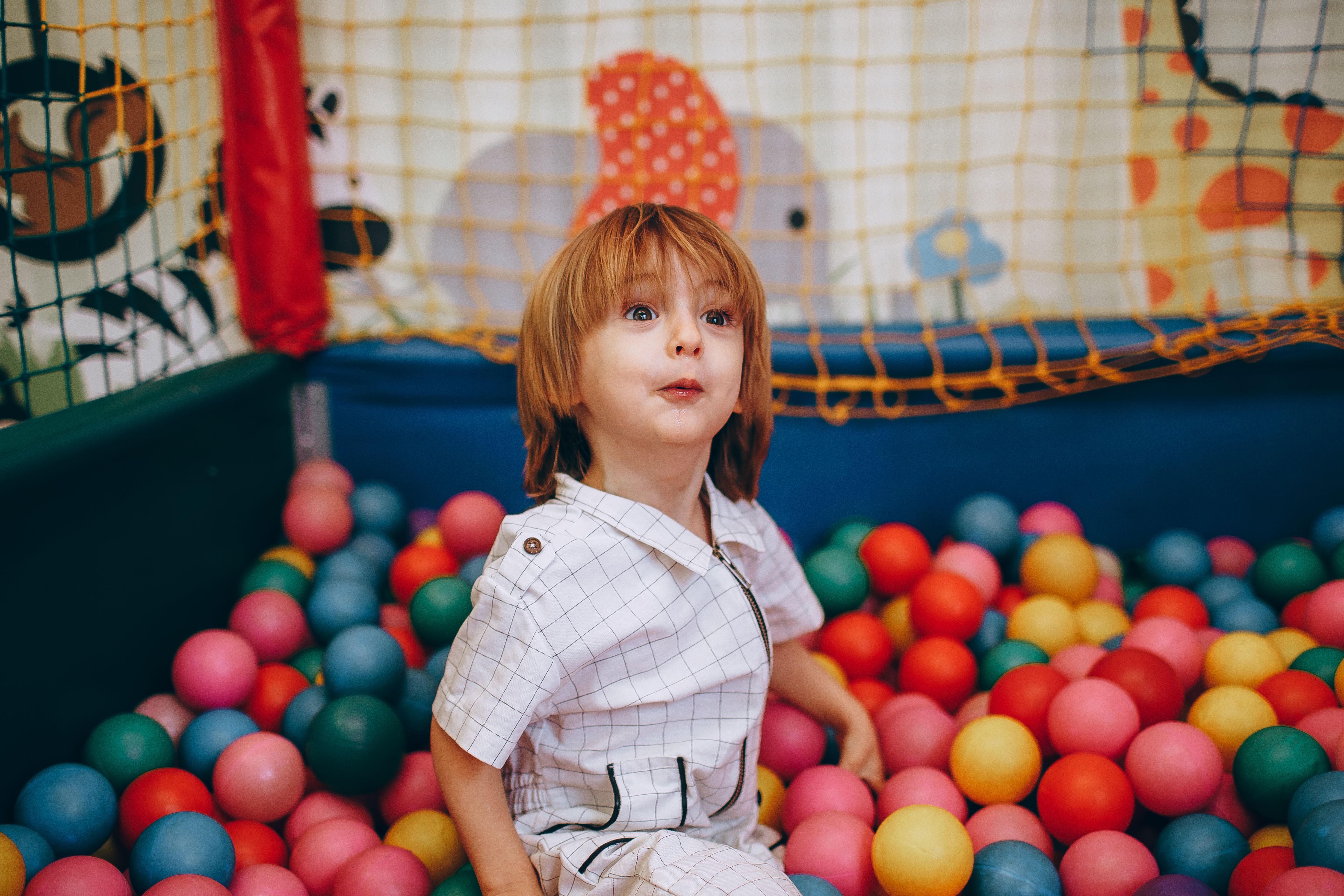 Boy in Shirt Sitting among Balls · Free Stock Photo