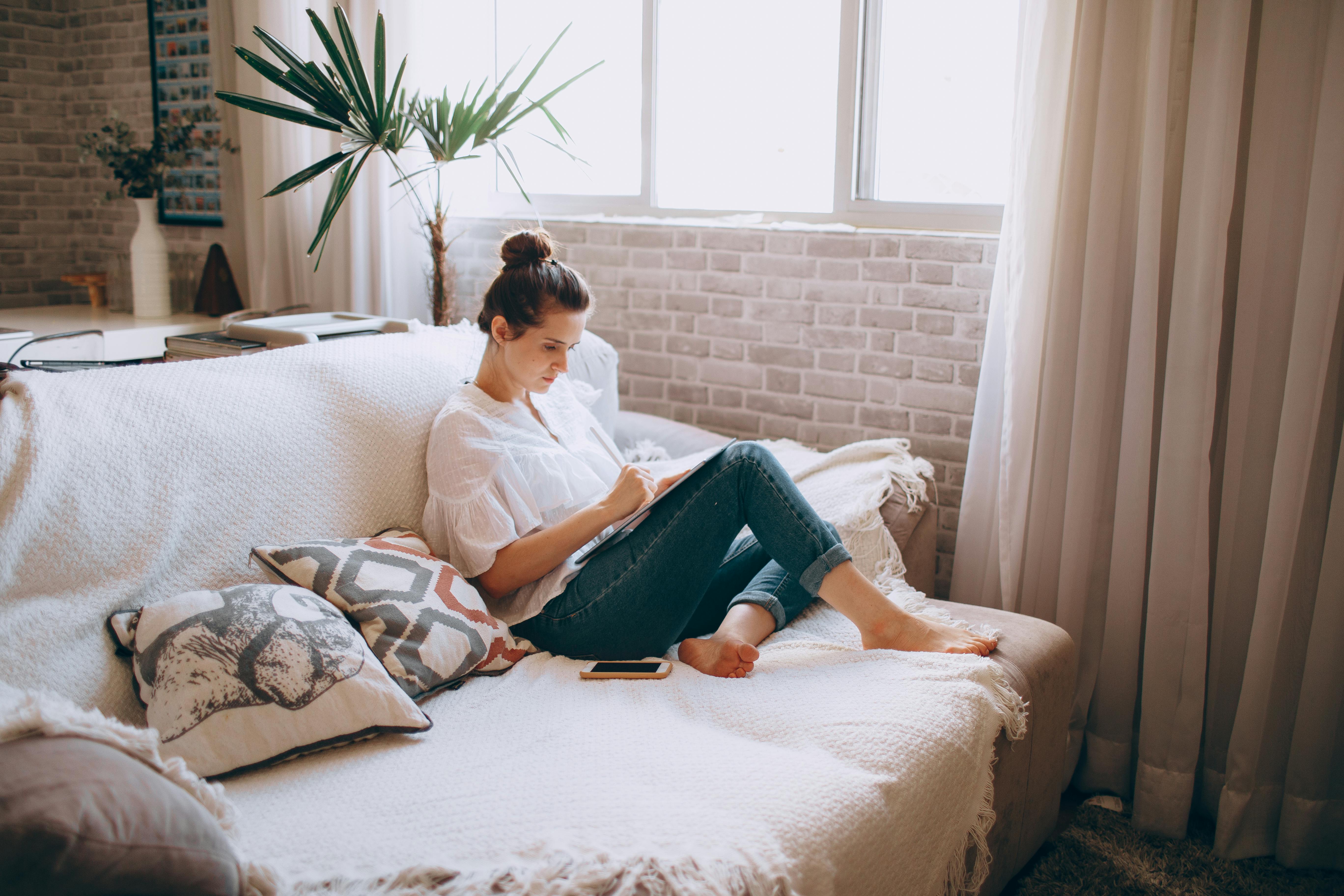 Woman Sitting on a Sofa and Using a Tablet · Free Stock Photo
