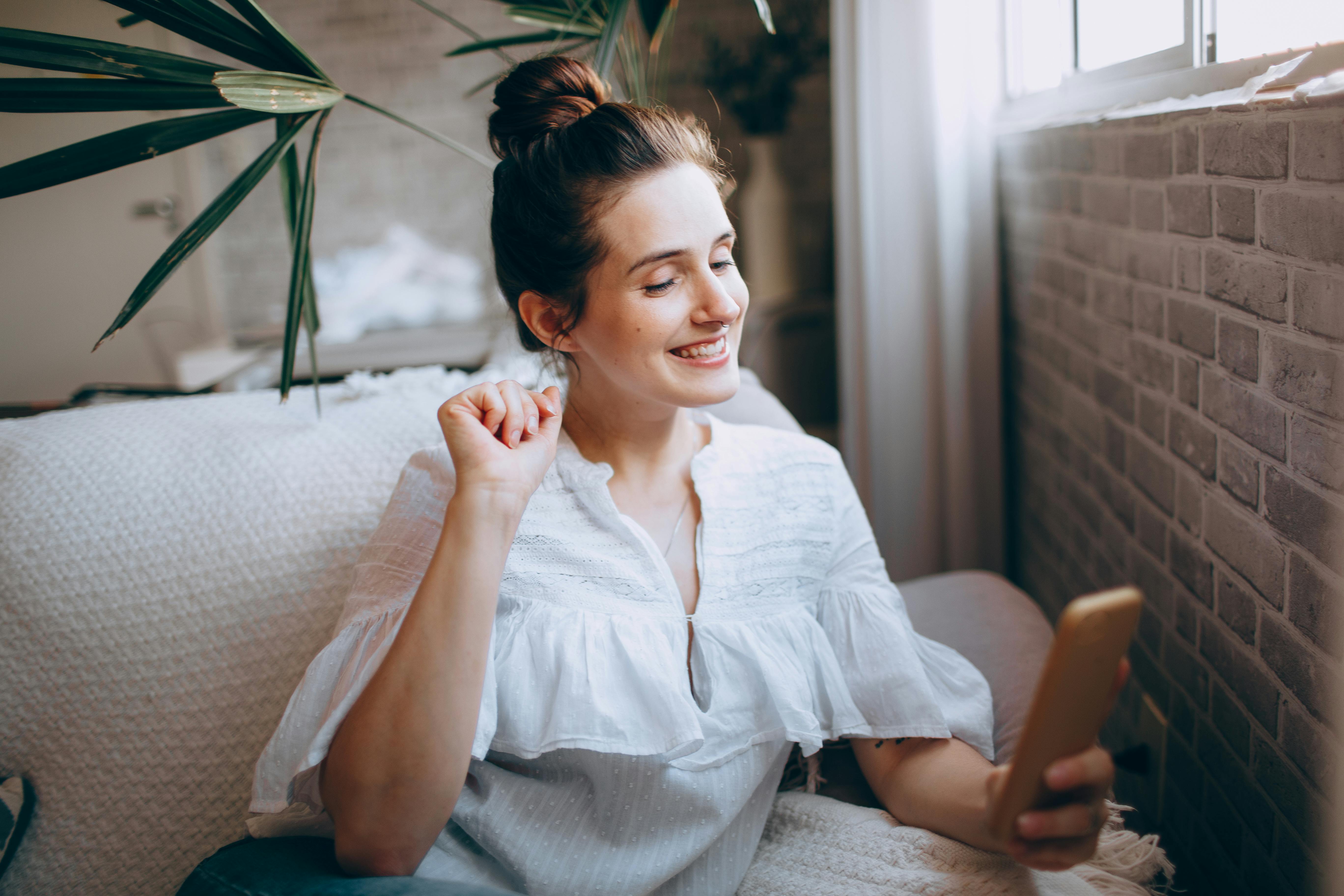 Woman Sitting Beside Window Holding Phone · Free Stock Photo