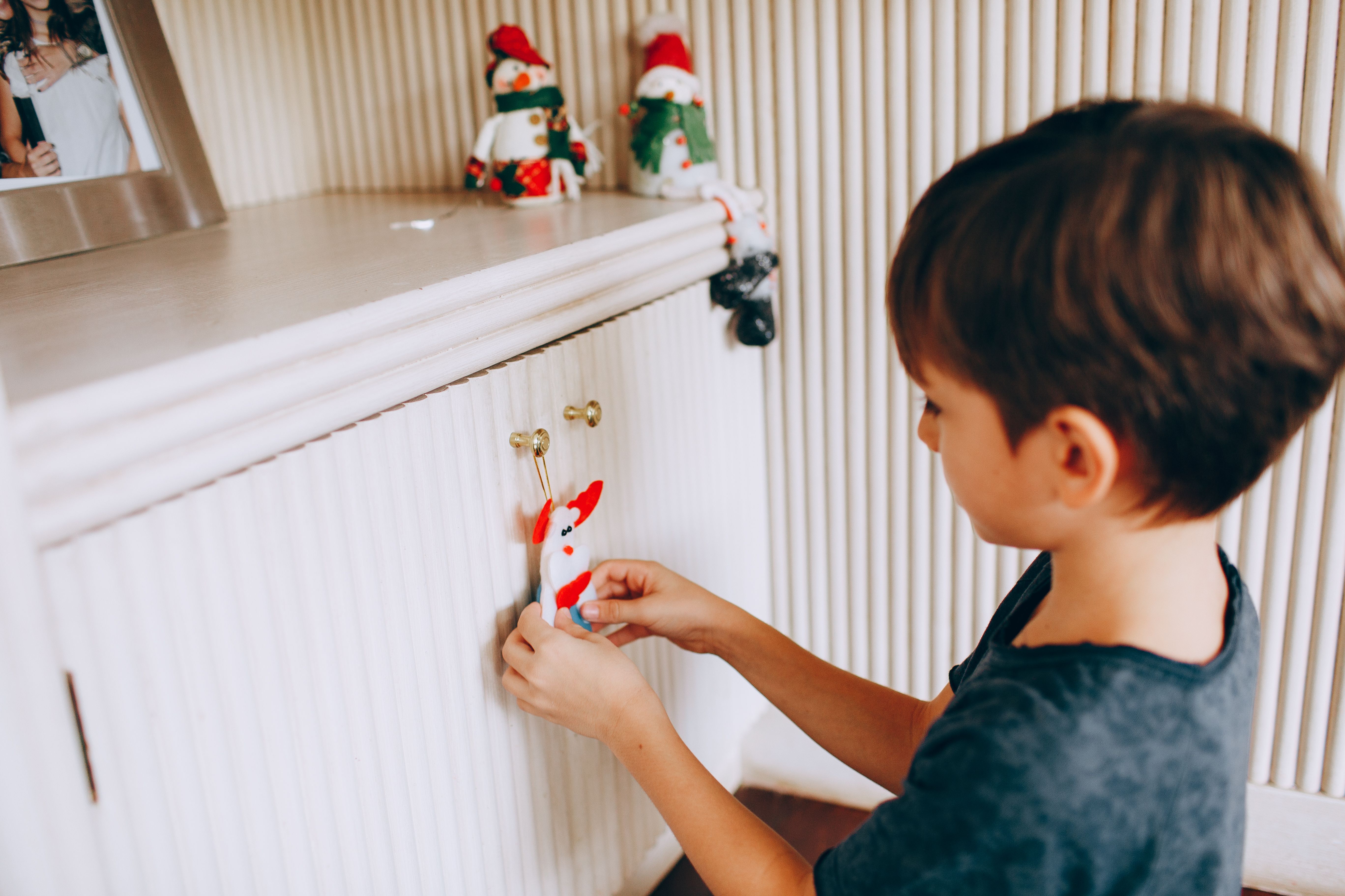 A young boy is putting a toy on the shelf · Free Stock Photo