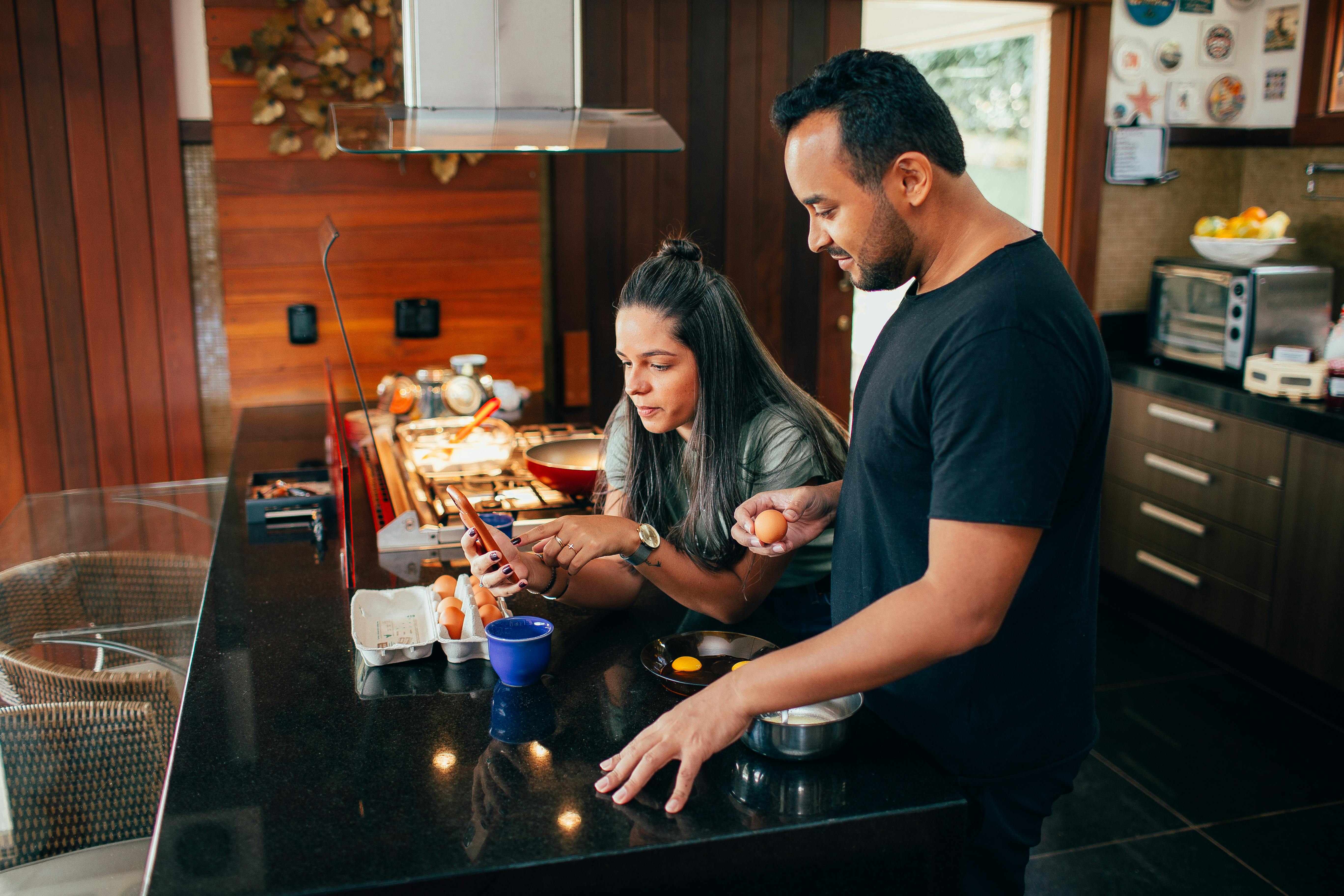 Young Couple Cooking in a Kitchen Following a Recipe on a Smartphone ...