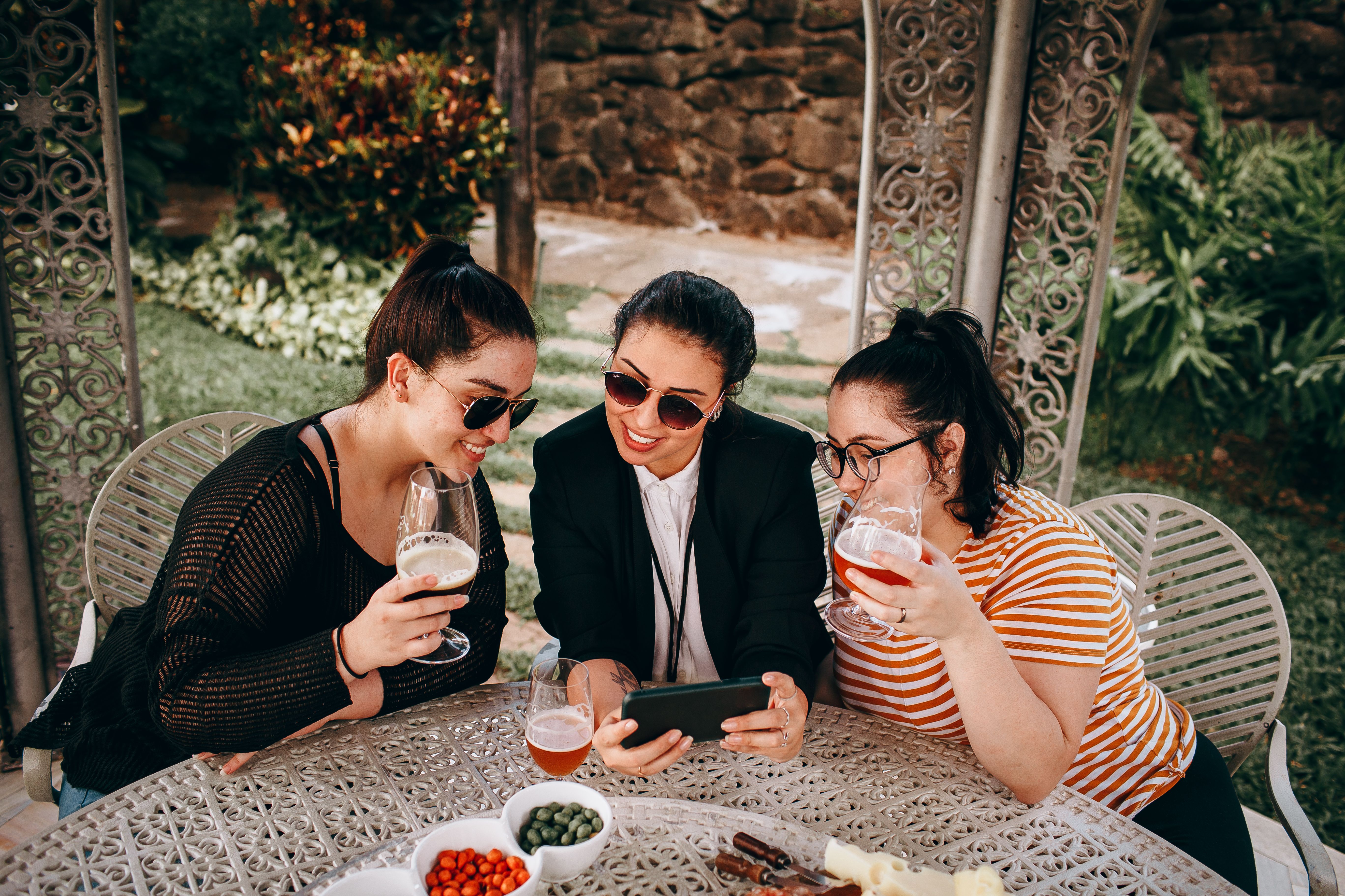 Three Women Socializing at Outdoor Patio Table · Free Stock Photo