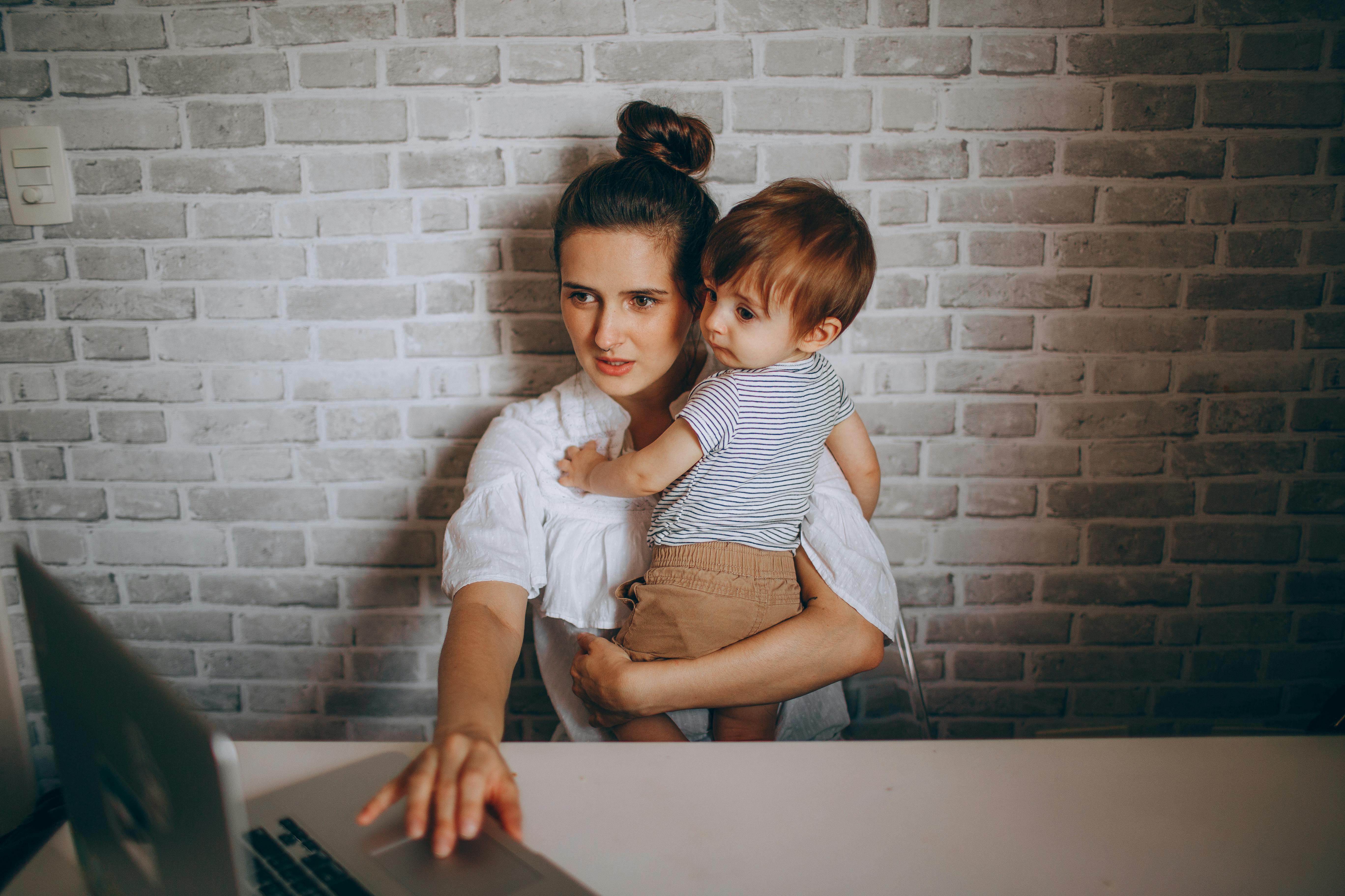 Focused mother working on laptop near disturbing daughter · Free Stock ...