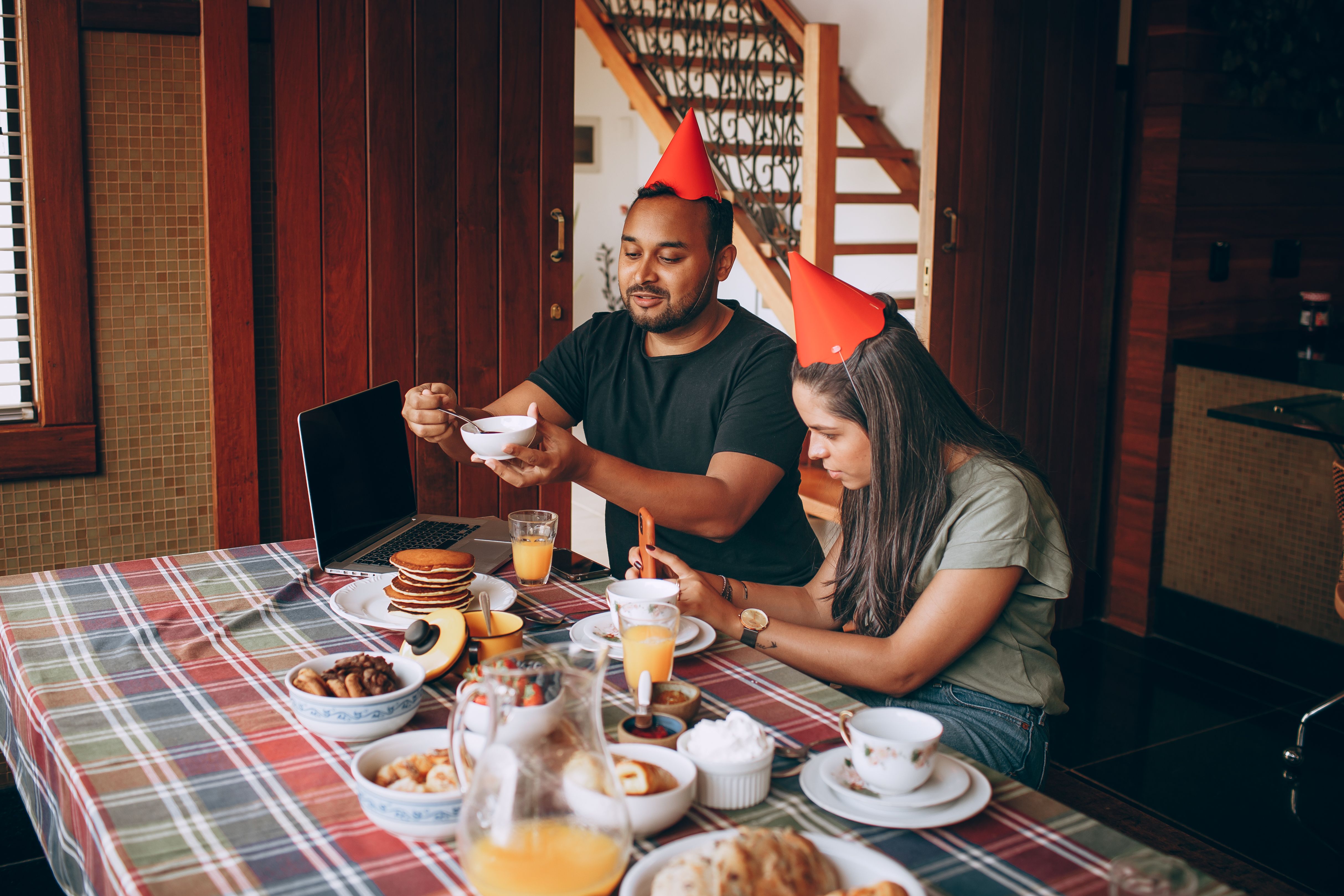 Couple in Party Hats Sitting at Table with Meal · Free Stock Photo