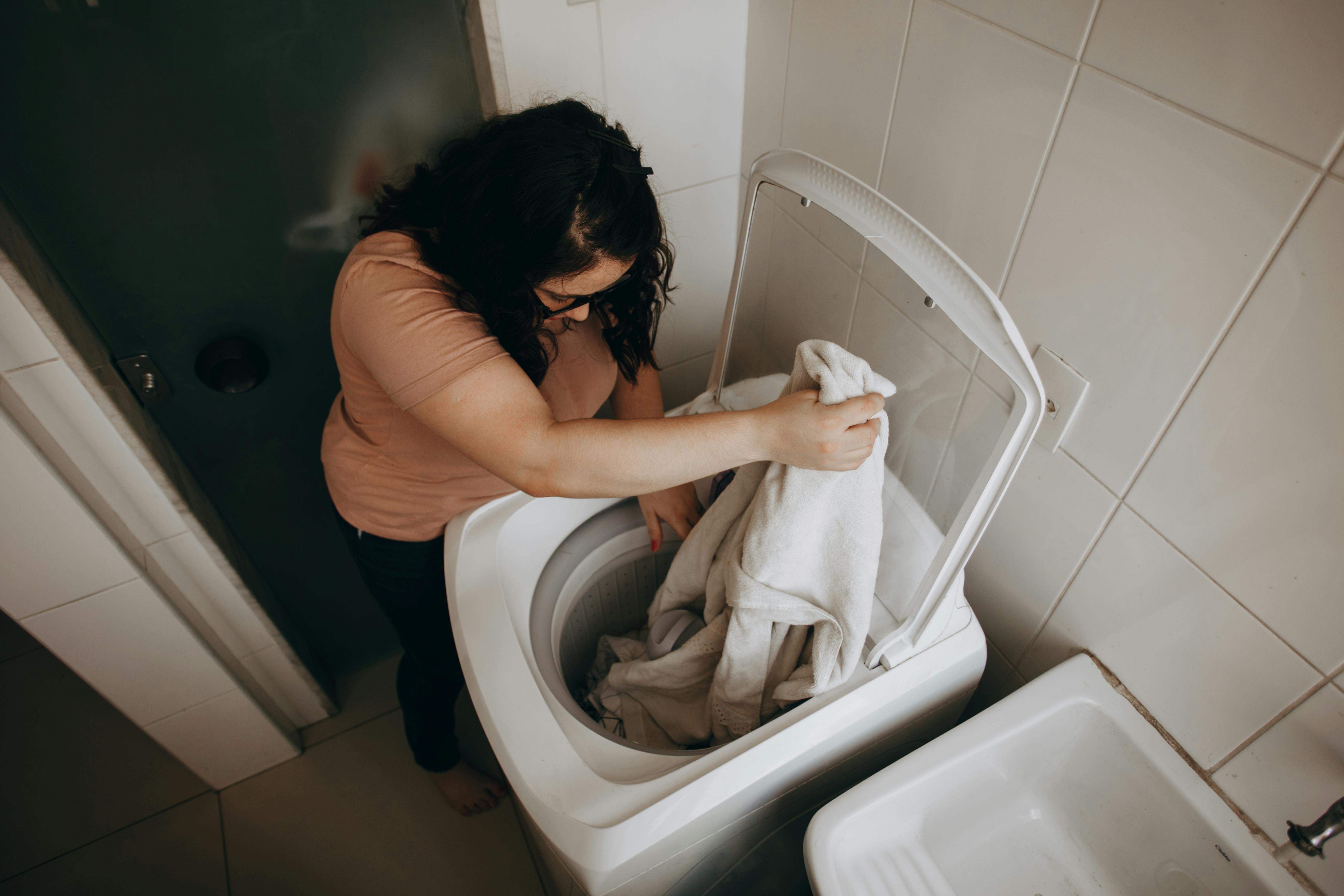 A Person Putting Clothes in a Washing Machine · Free Stock Photo