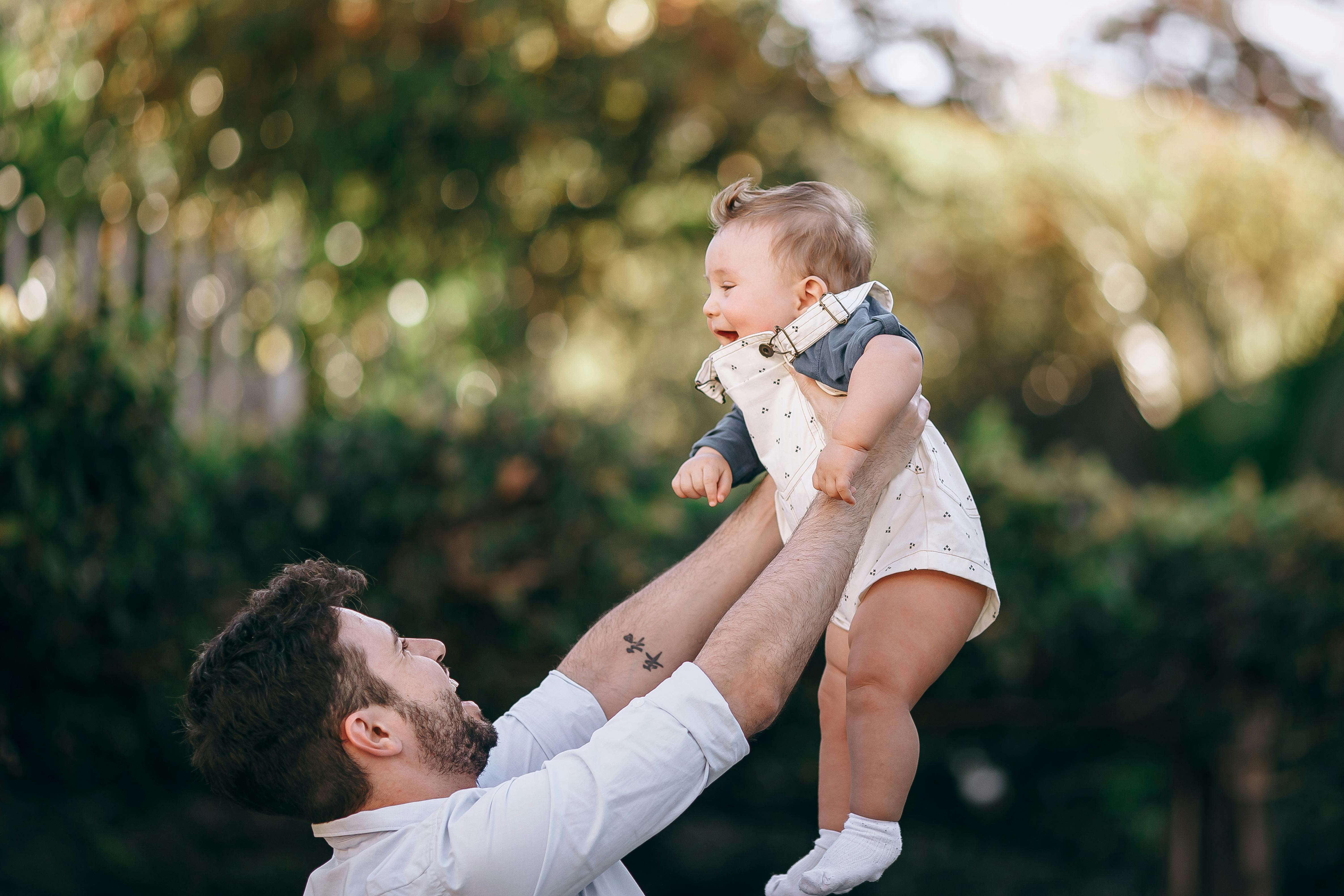 Father Lifting Newborn Son in Raised Arms · Free Stock Photo