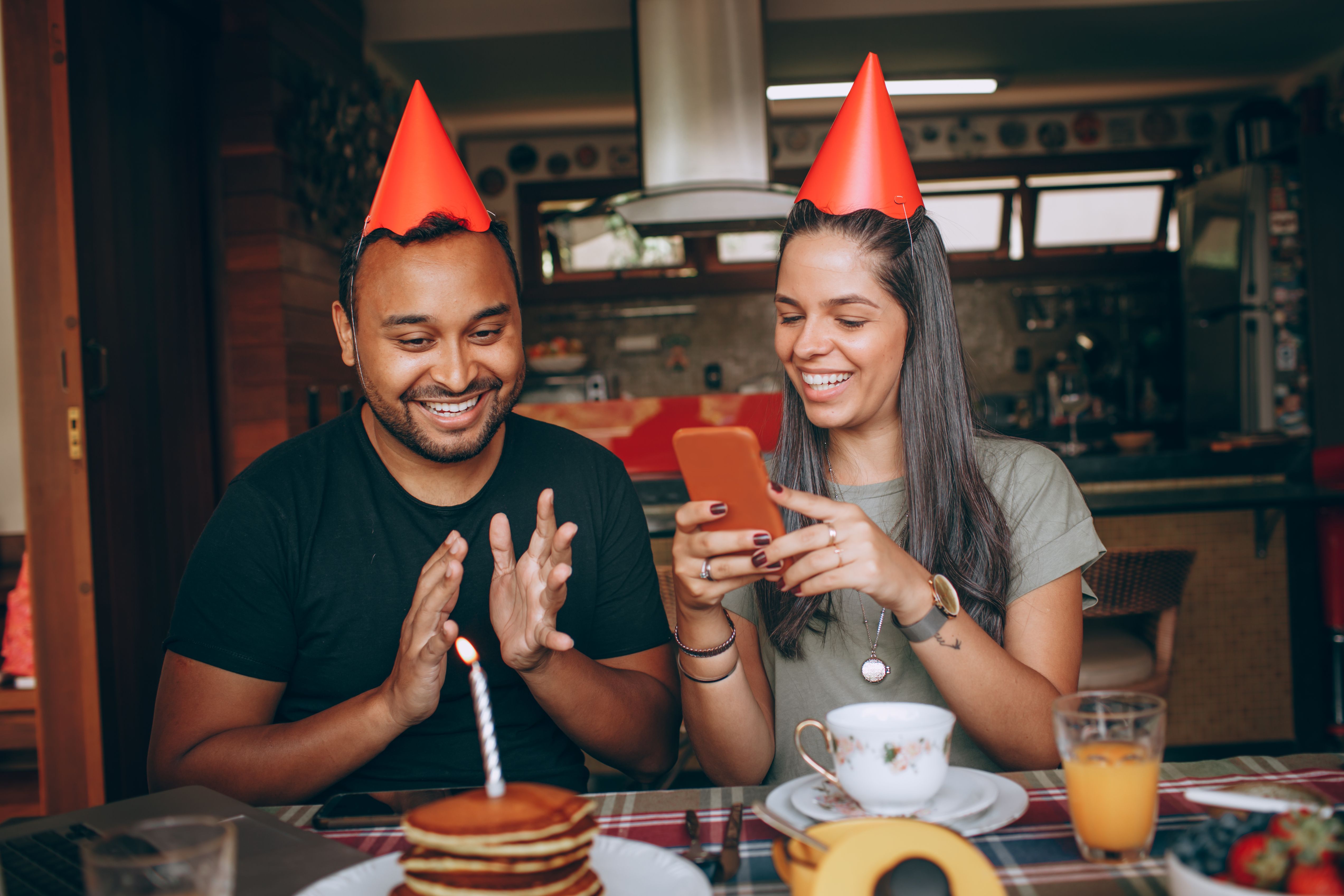 Two people wearing party hats and holding cell phones · Free Stock Photo