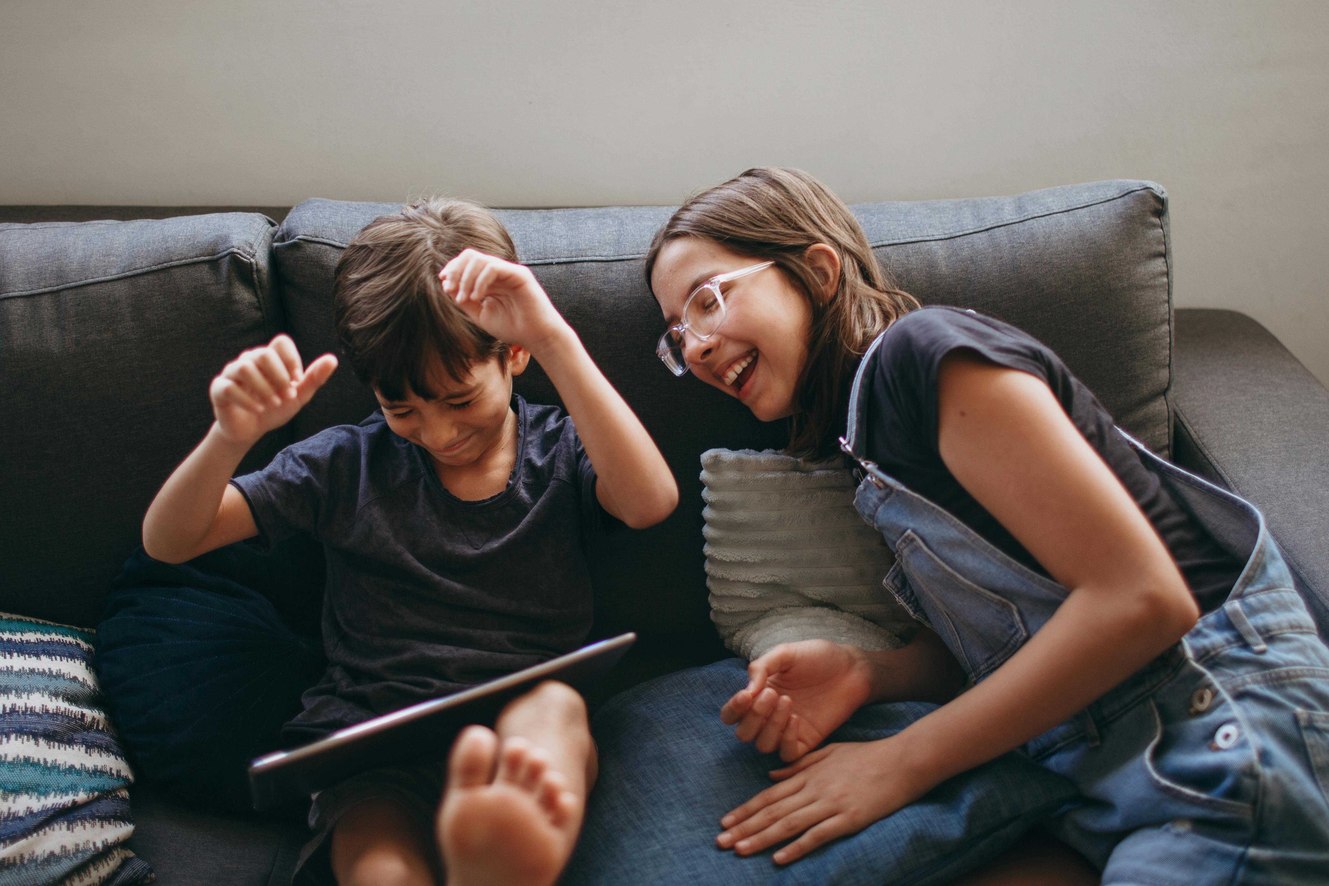 Laughing Brother and Sister Lying Down on Couch · Free Stock Photo