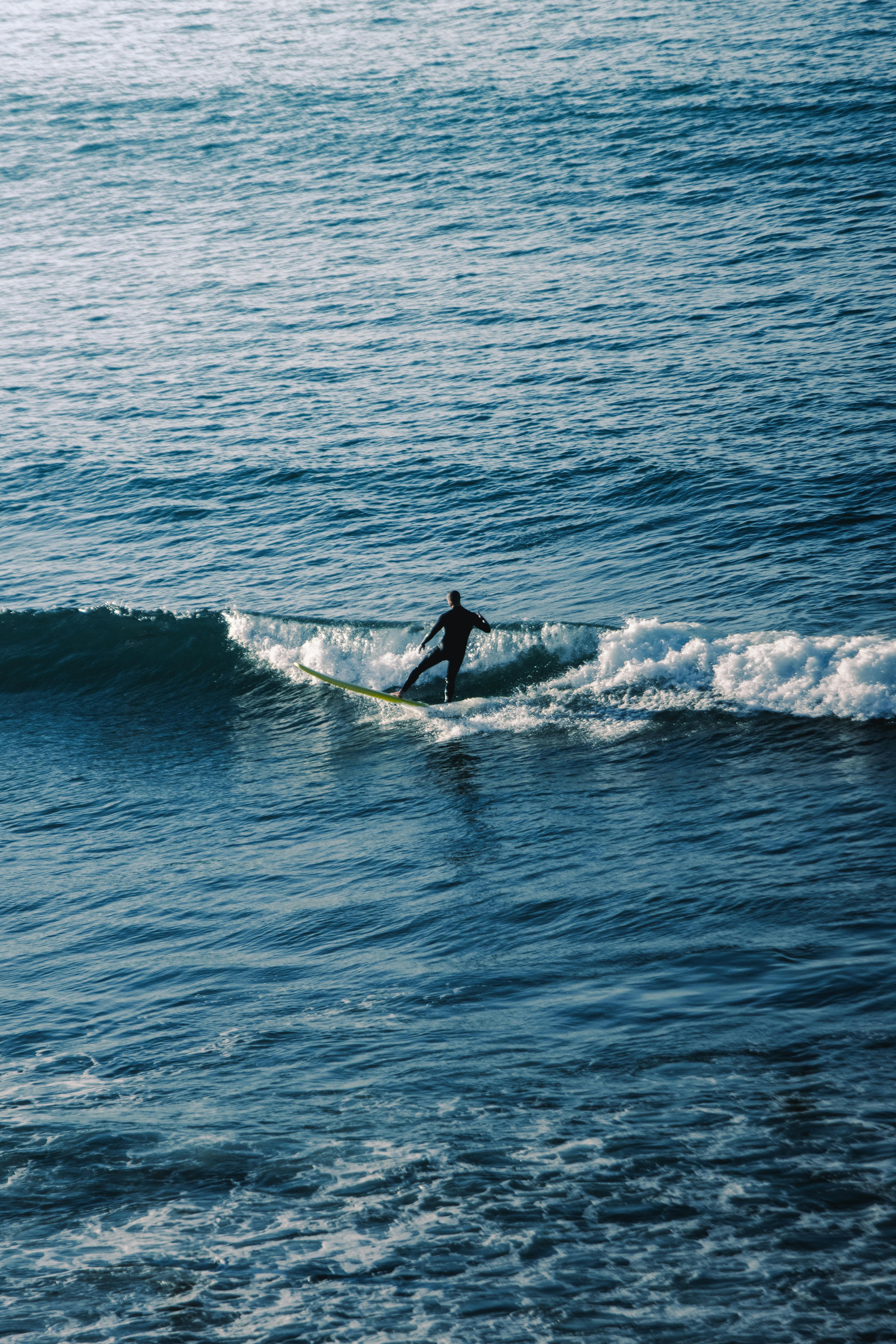 Man riding surfboard in wavy ocean · Free Stock Photo