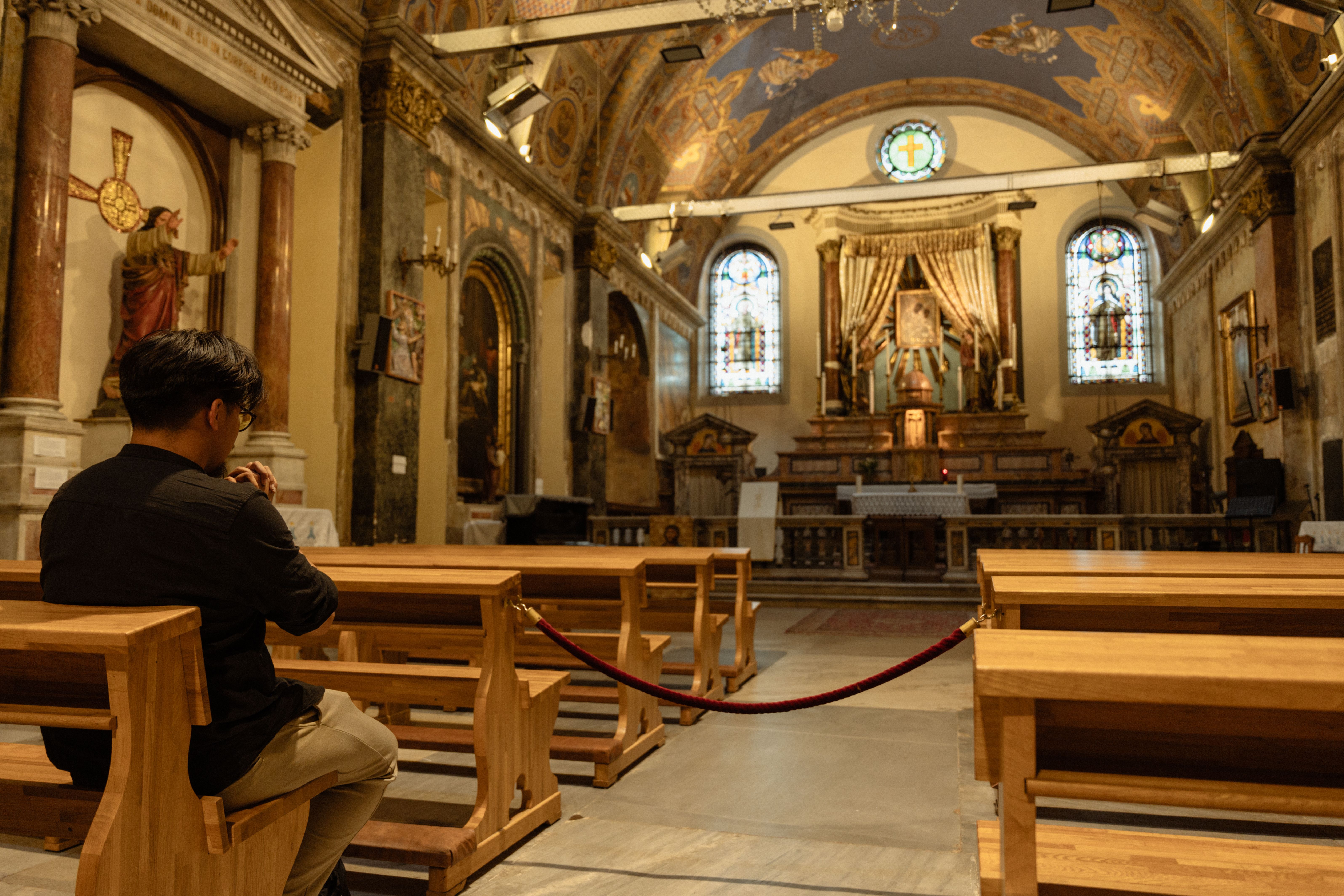 A man sitting in a church with wooden benches · Free Stock Photo