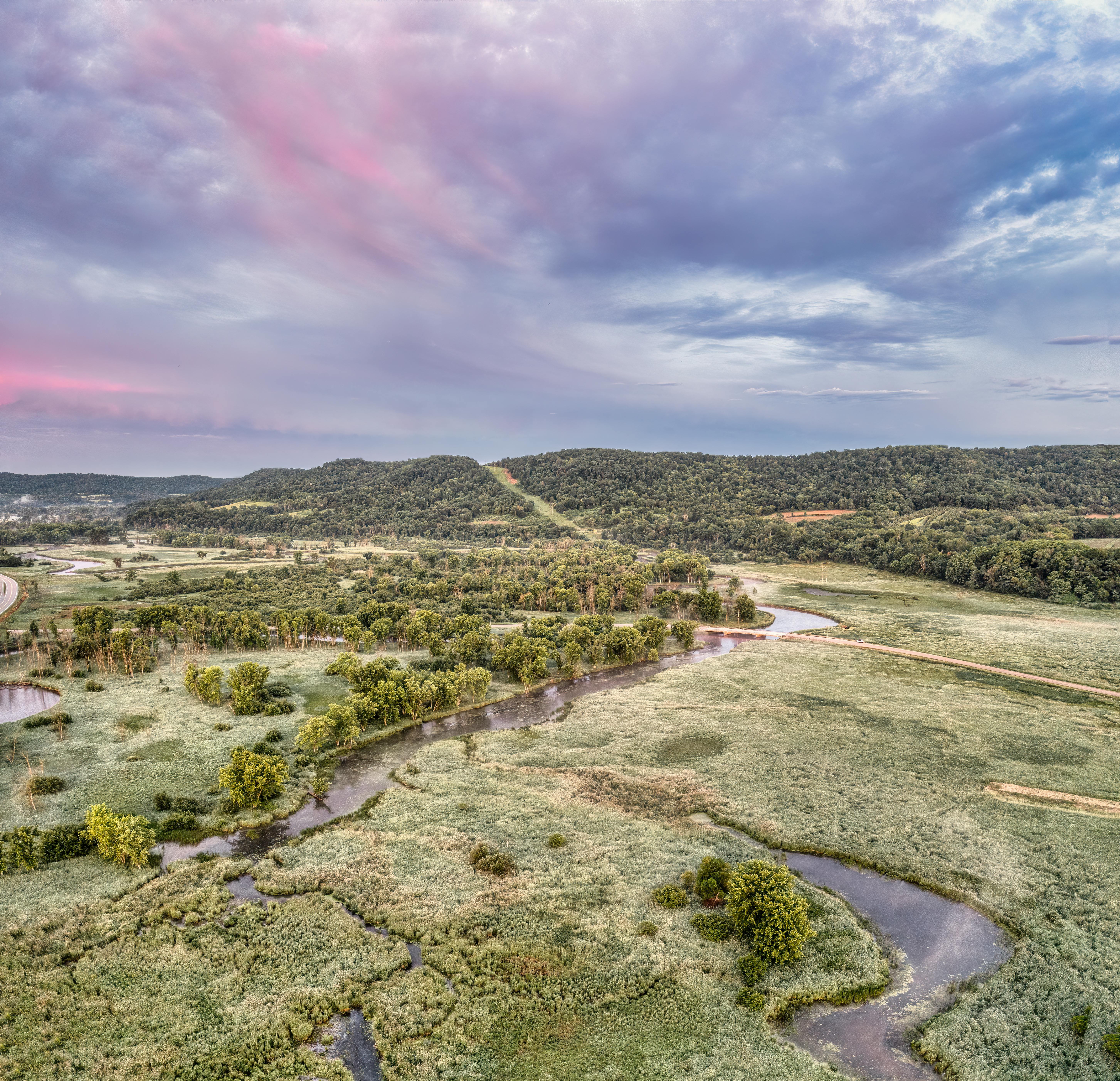 Aerial View of a Green Field with a Stream and Trees at Sunset · Free ...