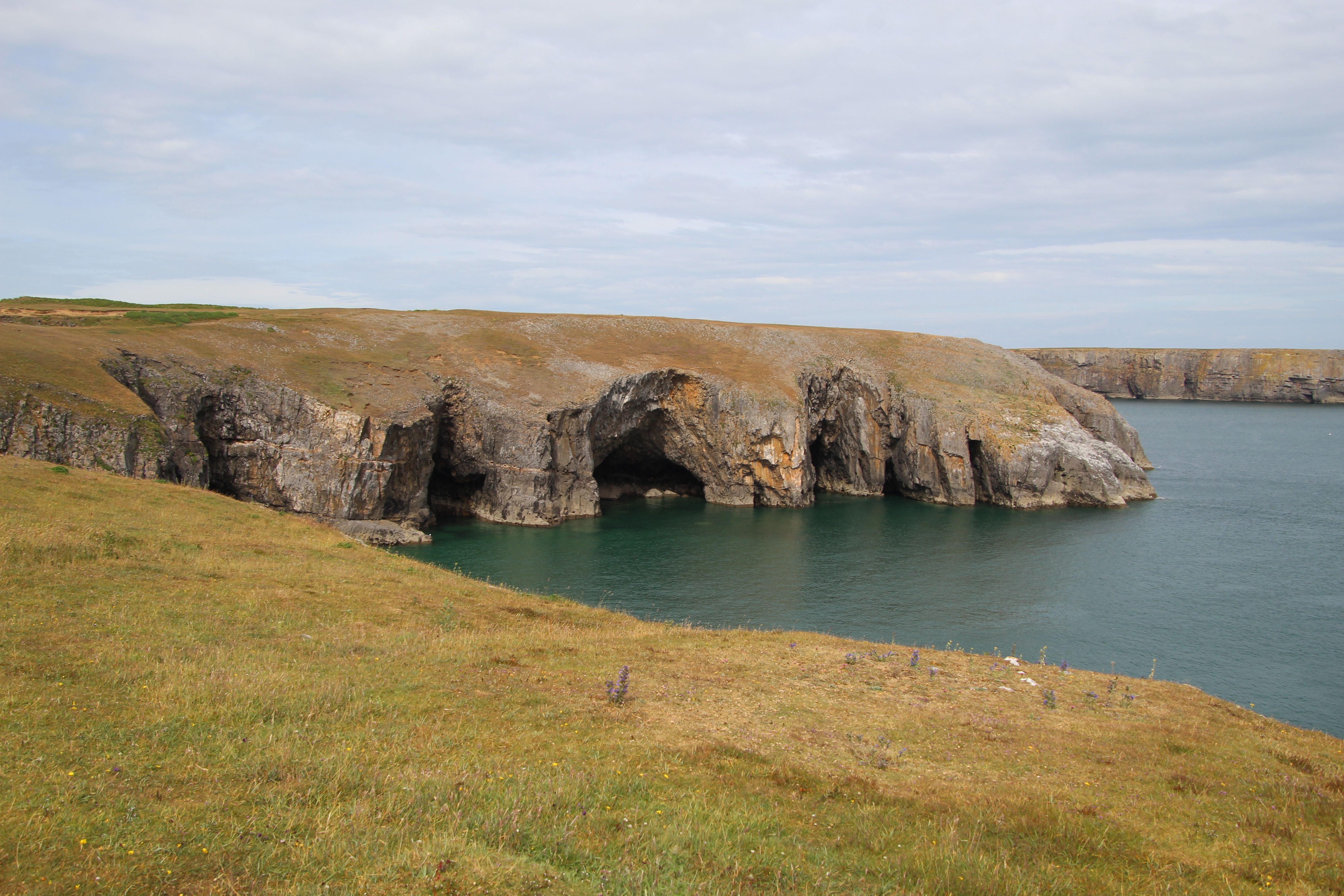 A large rock formation in the middle of a grassy field · Free Stock Photo