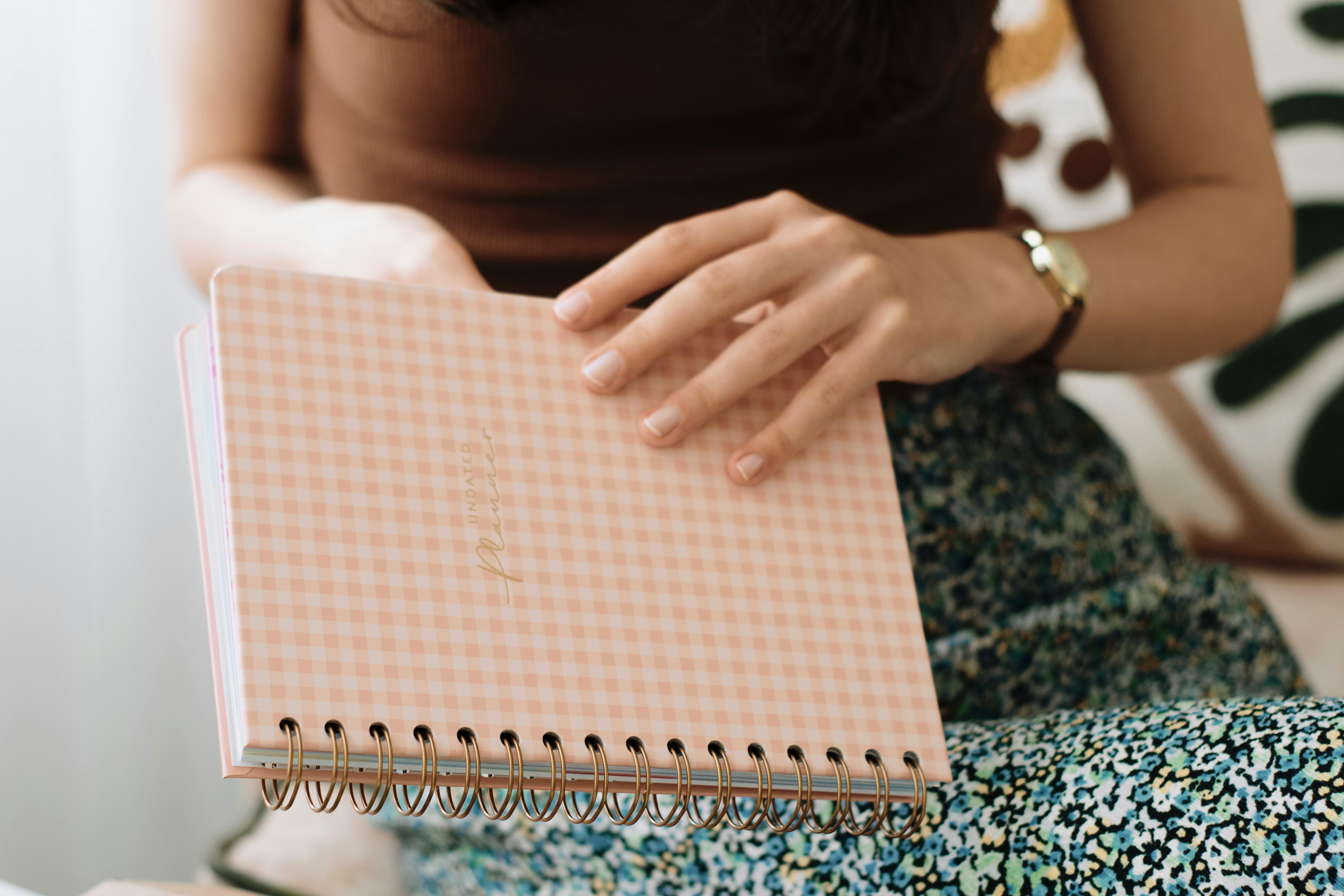 Opening a Notebook with a Checkered Cover · Free Stock Photo