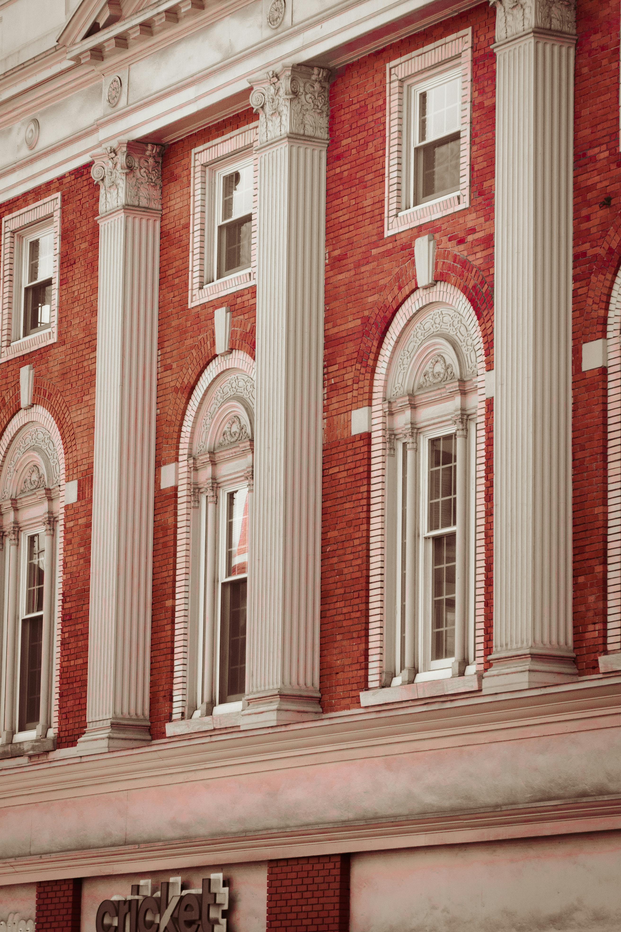 A red brick building with white columns and windows · Free Stock Photo