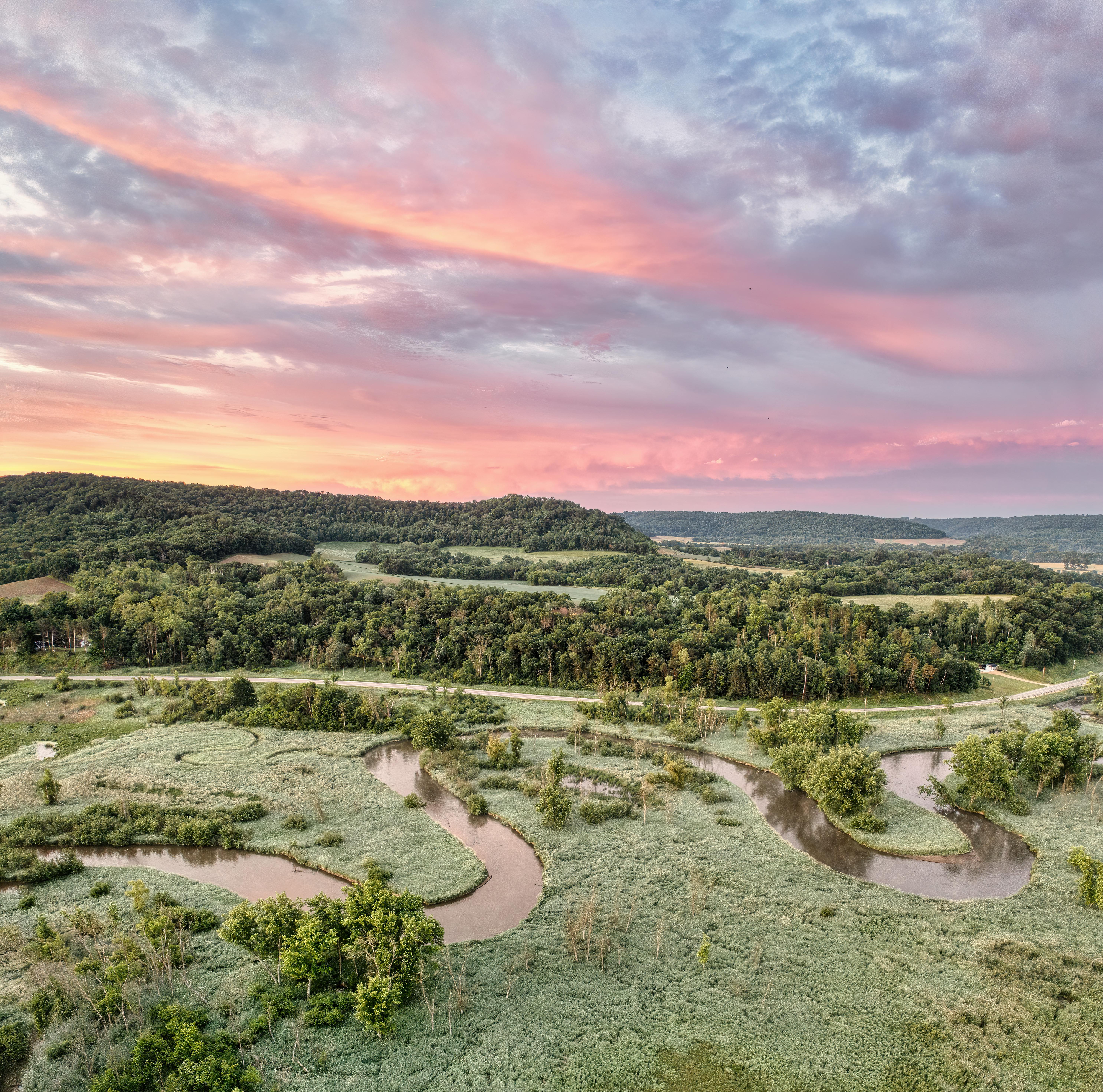 A sunset over a river and green fields · Free Stock Photo