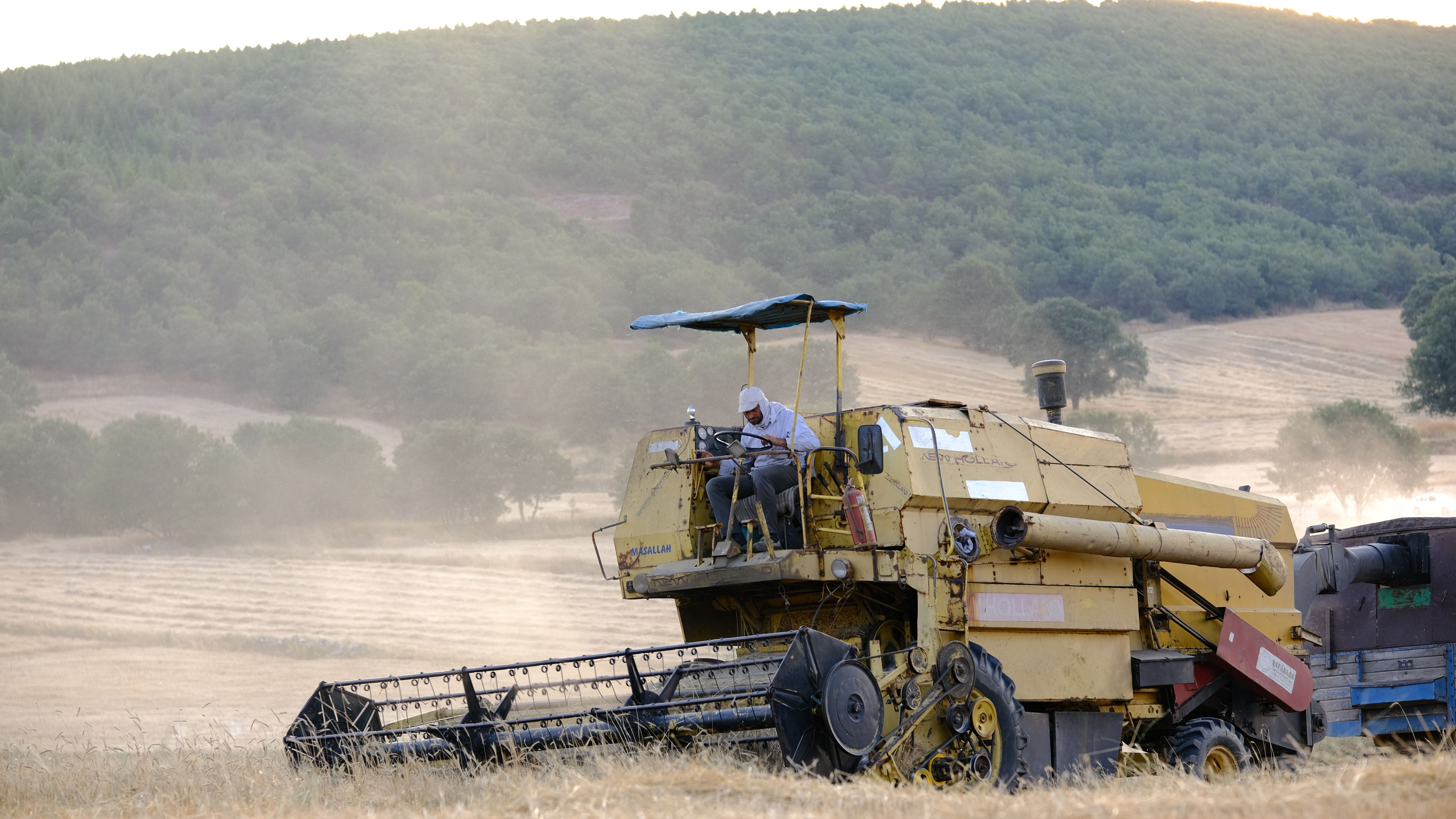 A man is driving a combine harvester through a field · Free Stock Photo