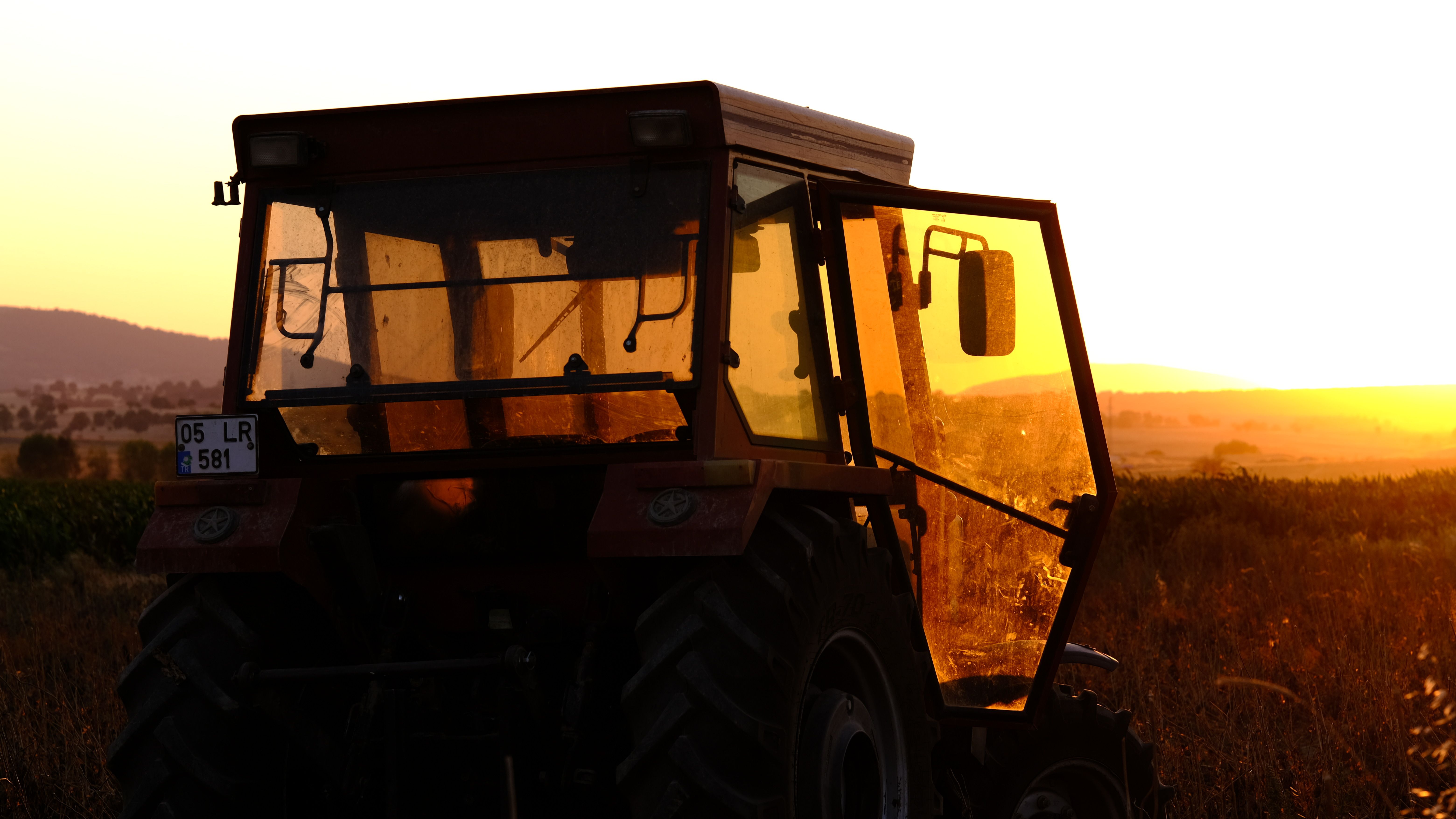 A tractor is parked in a field at sunset · Free Stock Photo