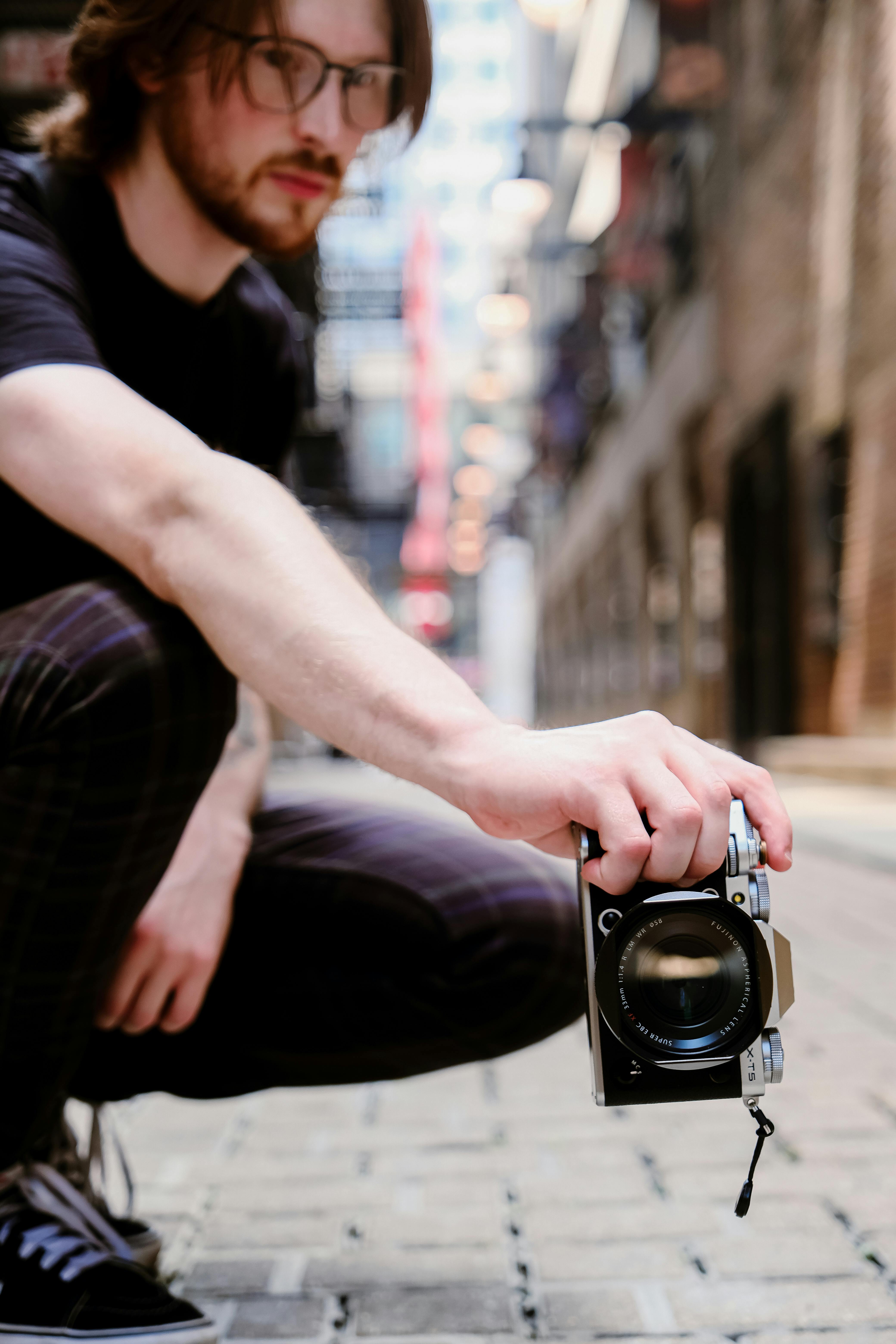 Photographer Crouching on the Sidewalk and Taking Photos · Free Stock Photo