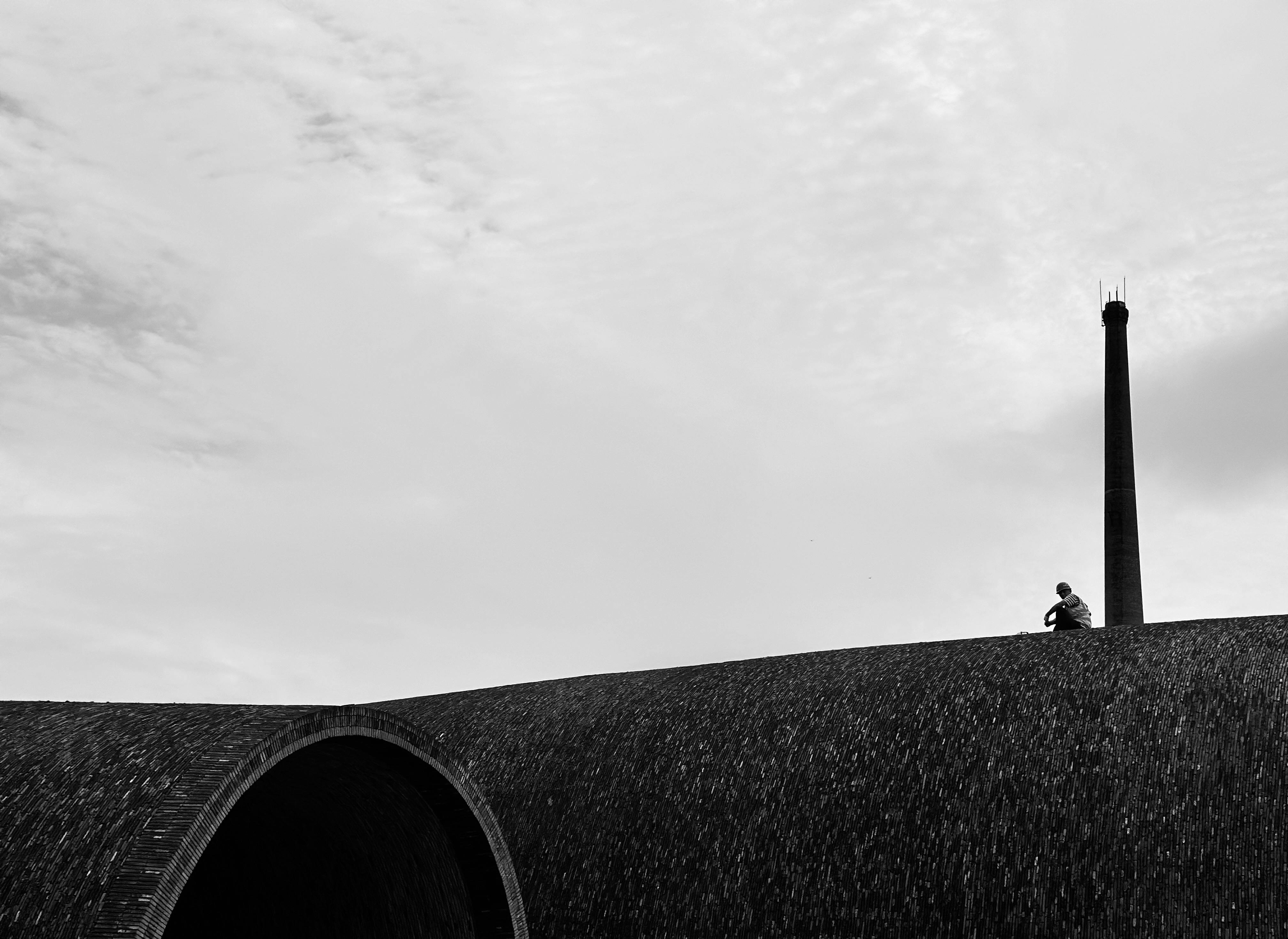 Man Sitting on the Roof of a Cylindrical Building · Free Stock Photo