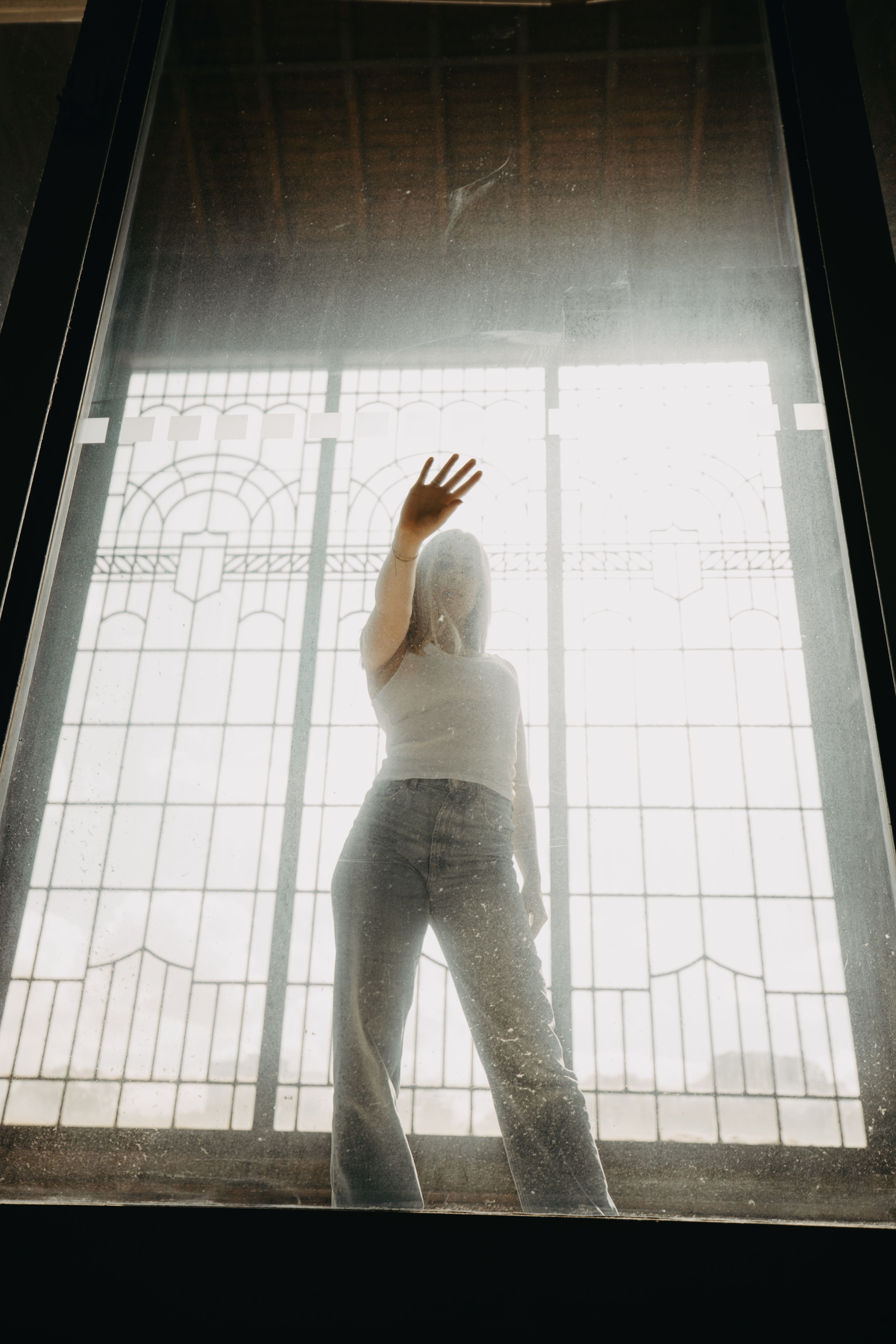Woman Standing with Hand Raised behind Window · Free Stock Photo