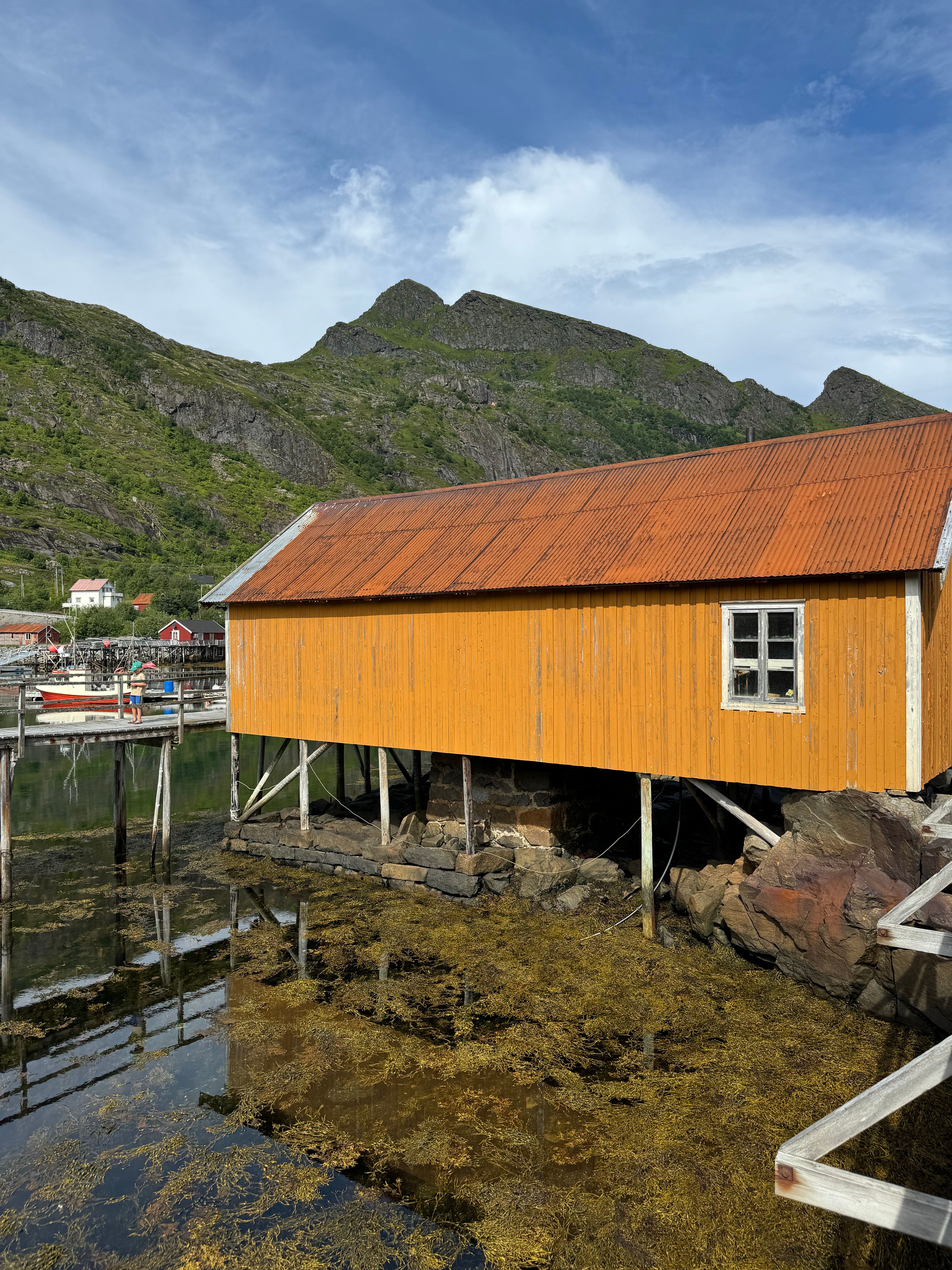 A small wooden house sits on the shore of a body of water · Free Stock ...