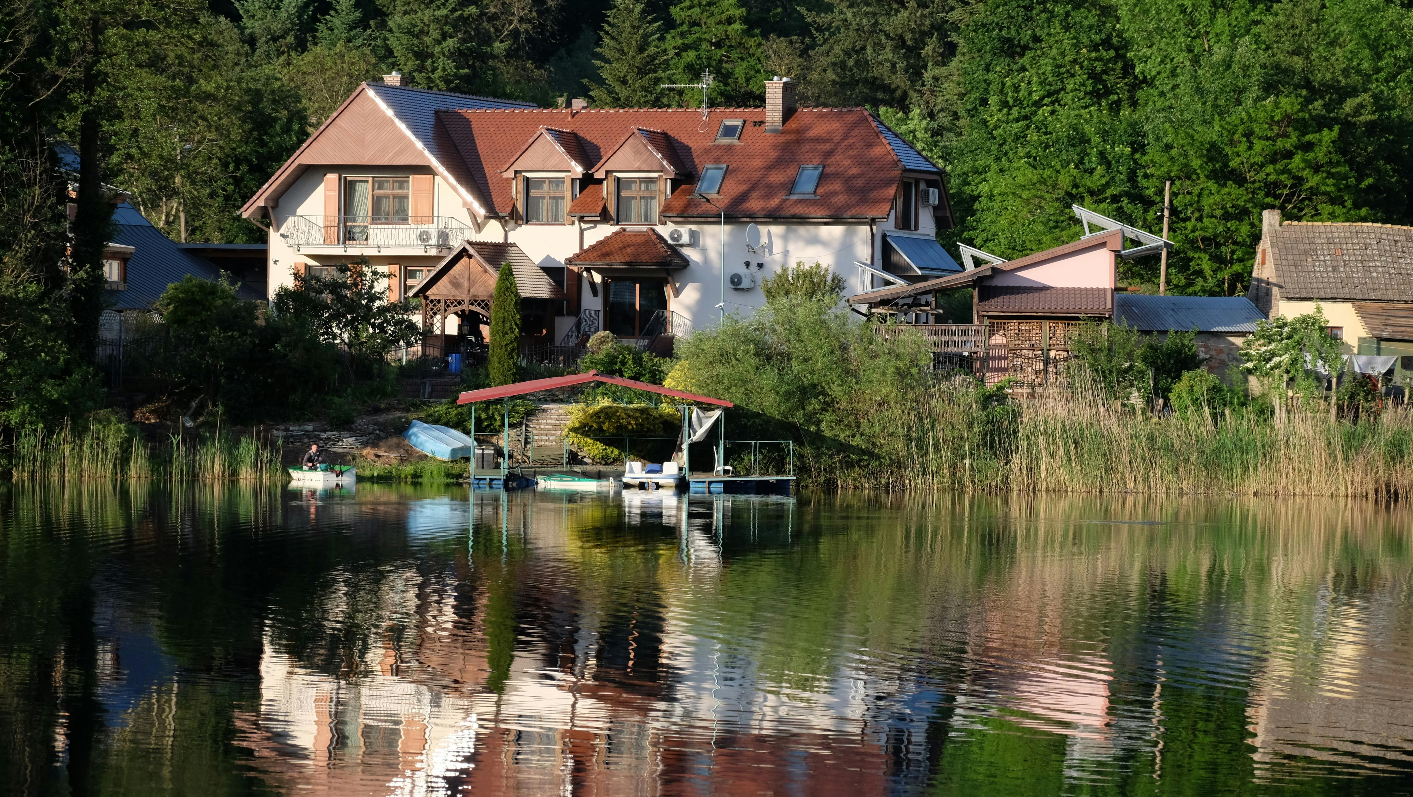 A house is reflected in the water in front of a lake · Free Stock Photo