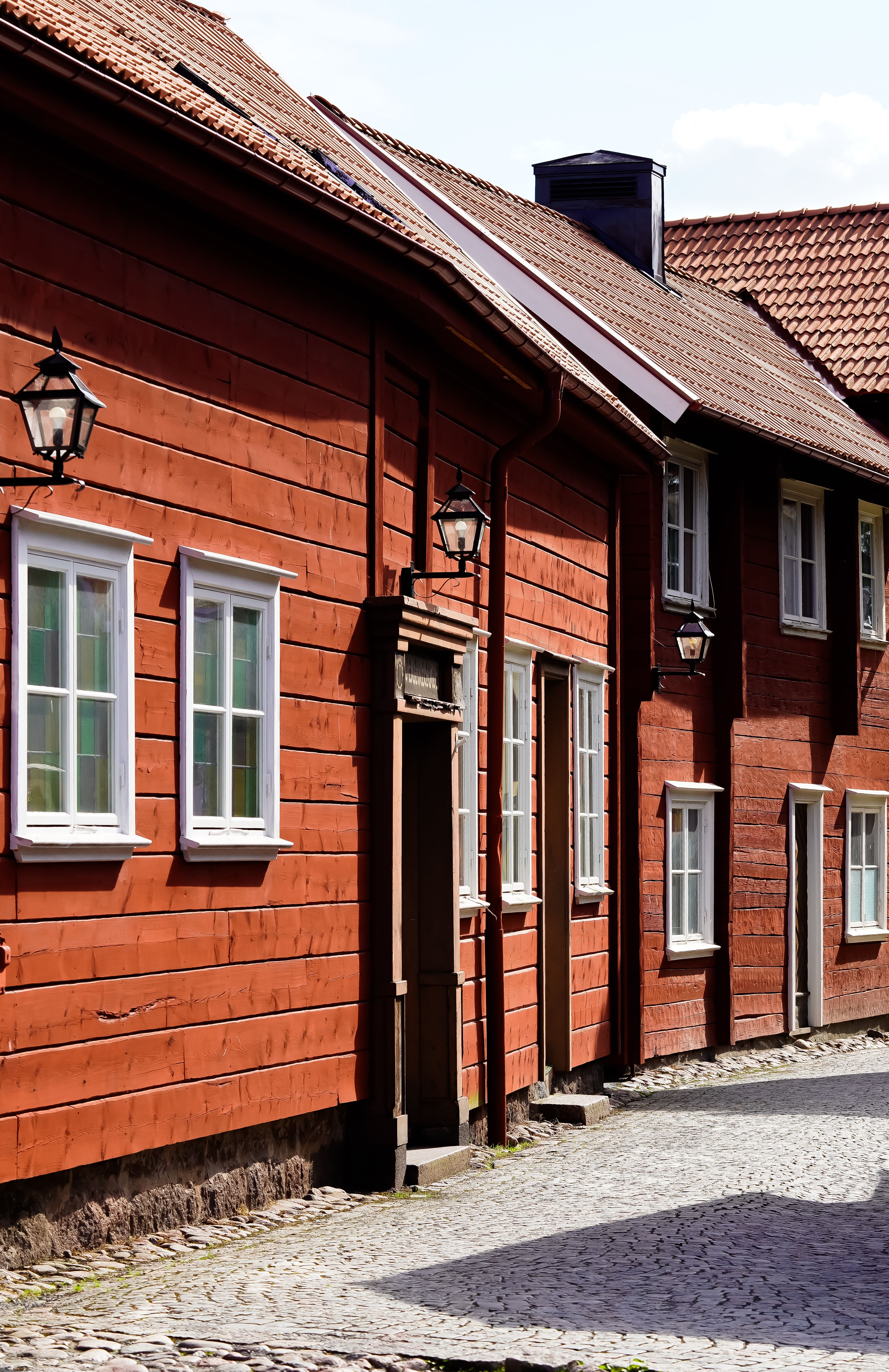 A cobblestone street with a row of red wooden houses · Free Stock Photo