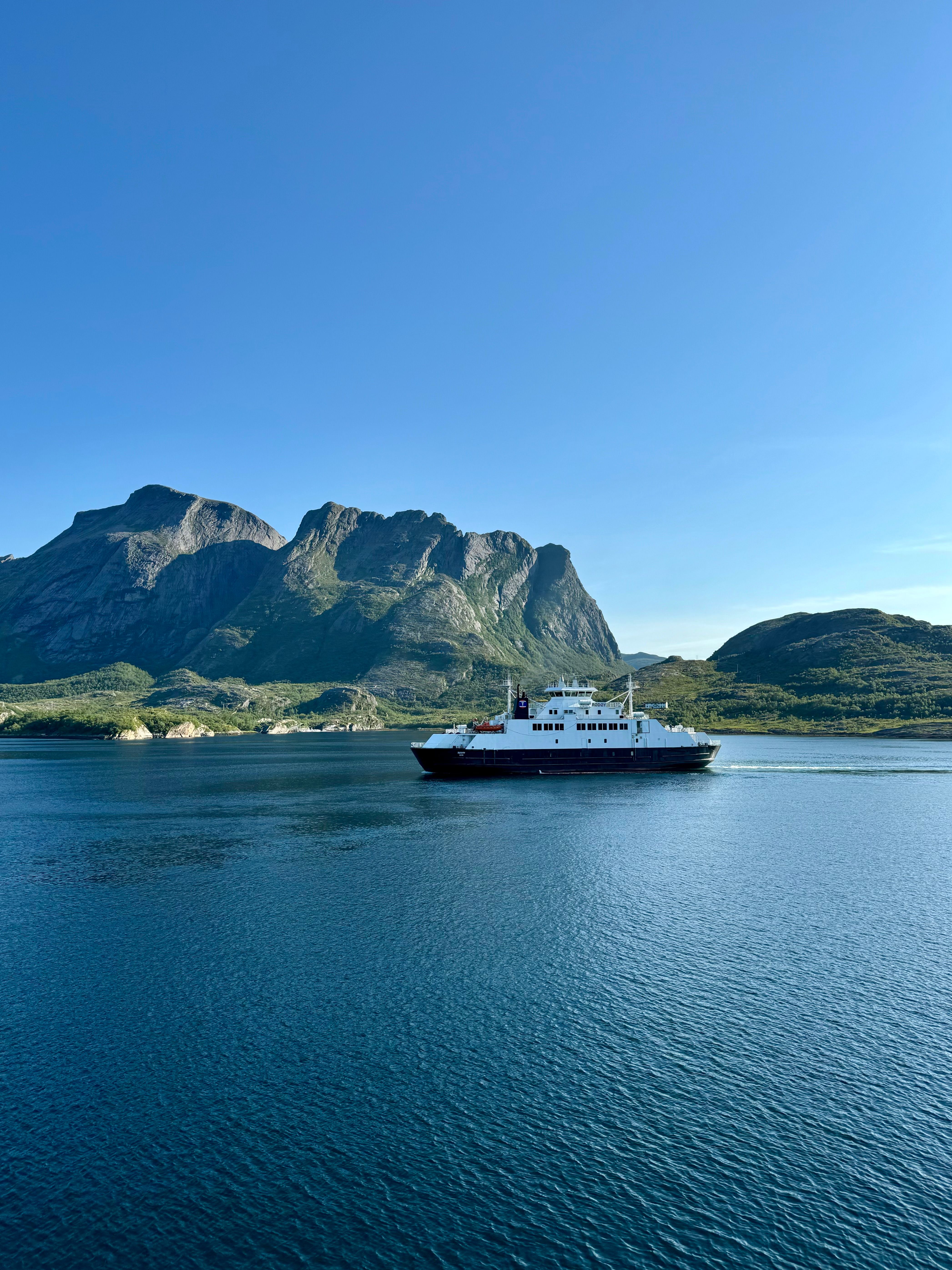 A boat is traveling through the water near mountains · Free Stock Photo