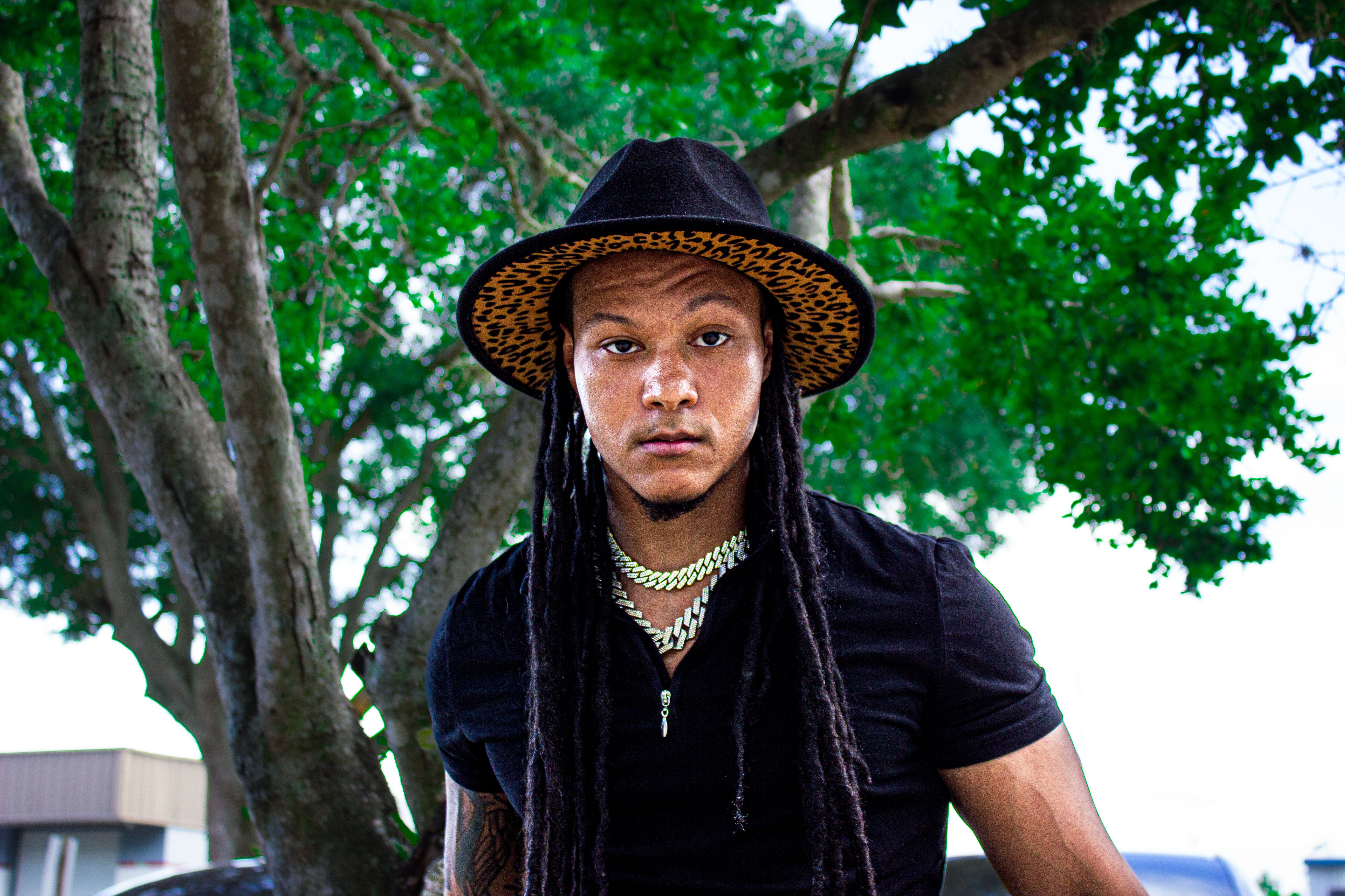 A man with dreadlocks wearing a hat and shirt · Free Stock Photo