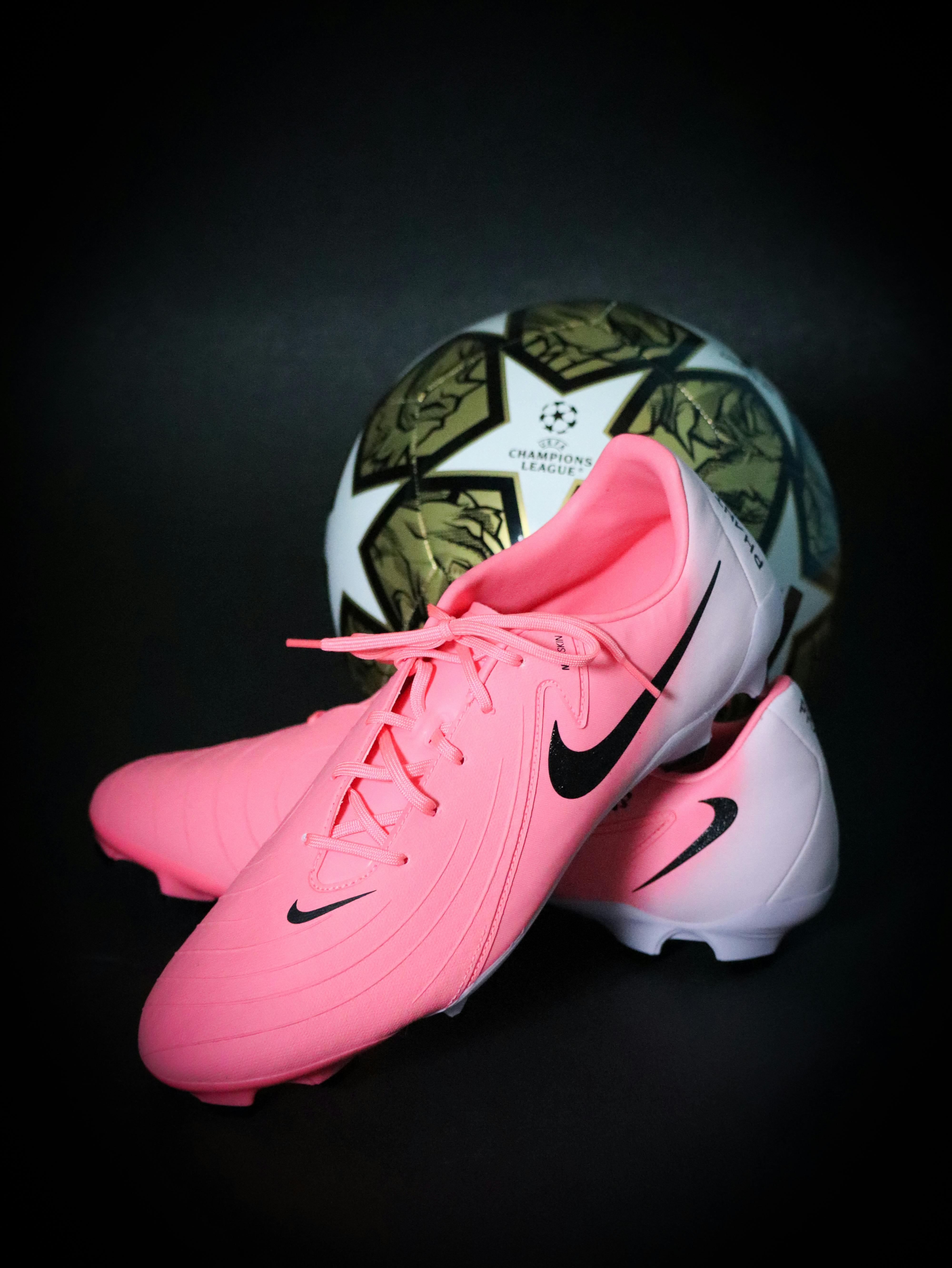 A pair of pink soccer shoes next to a soccer ball · Free Stock Photo