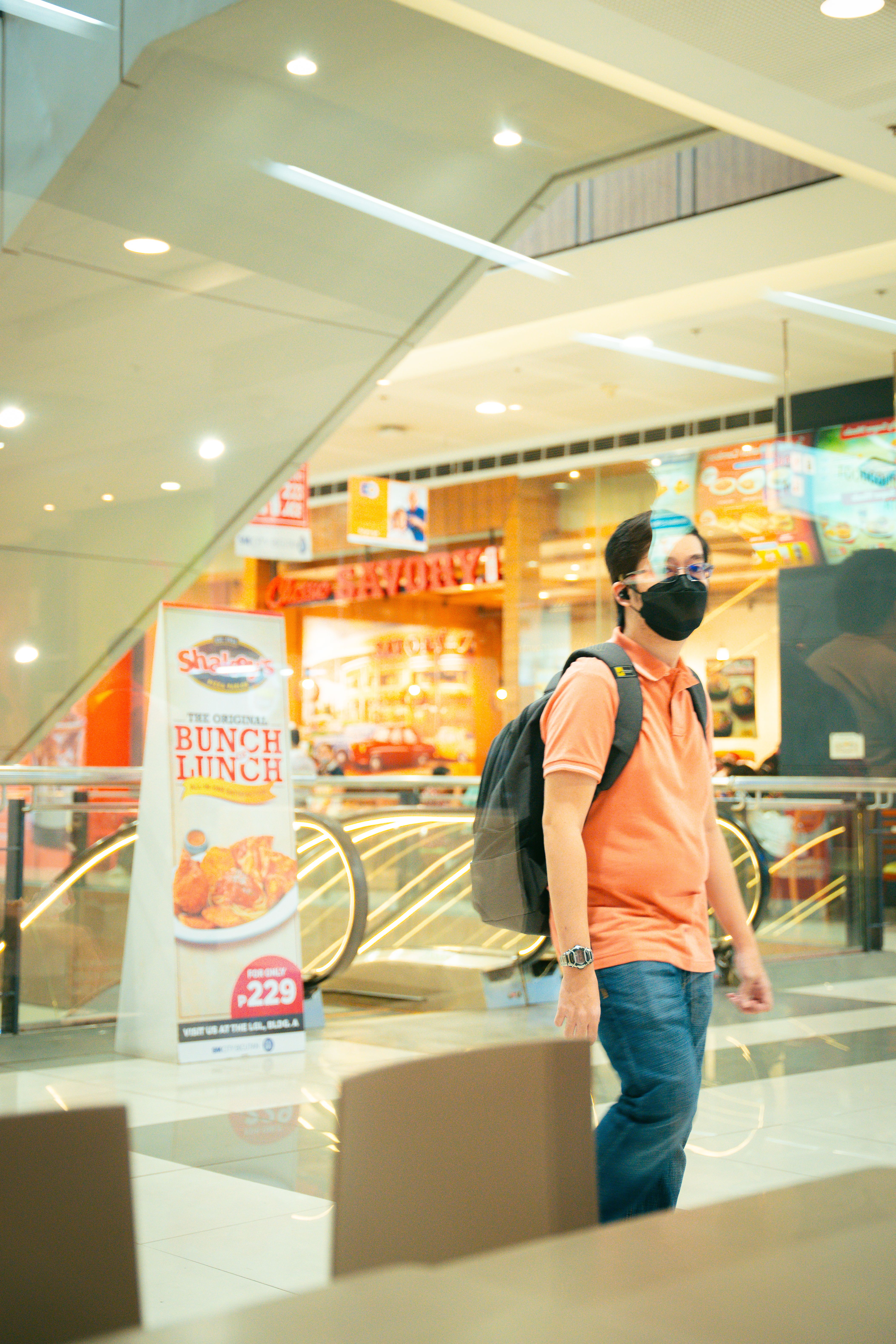 A man wearing a mask walks through a shopping mall · Free Stock Photo