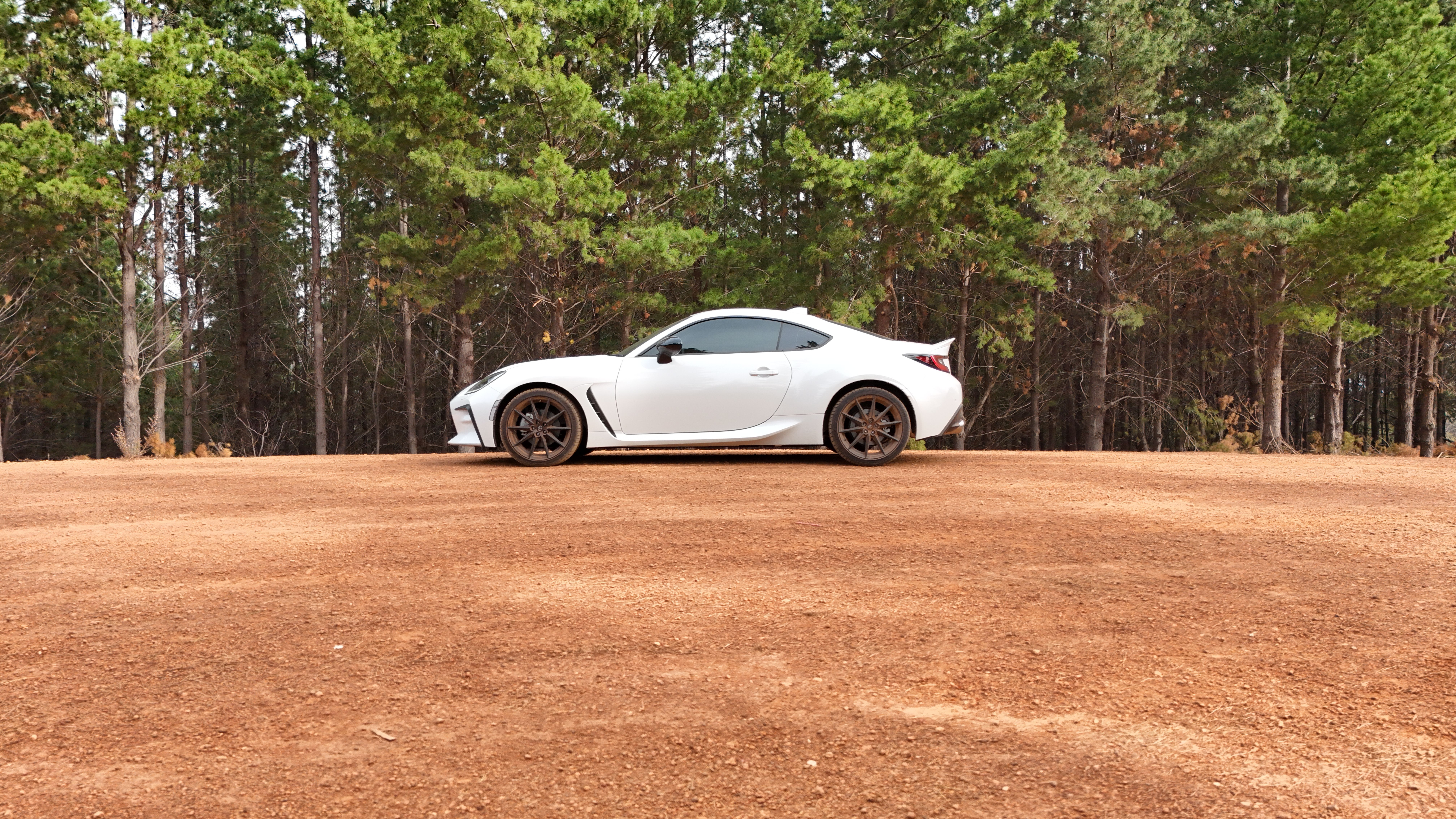 White Sports Car on Dirt Road in Forest · Free Stock Photo
