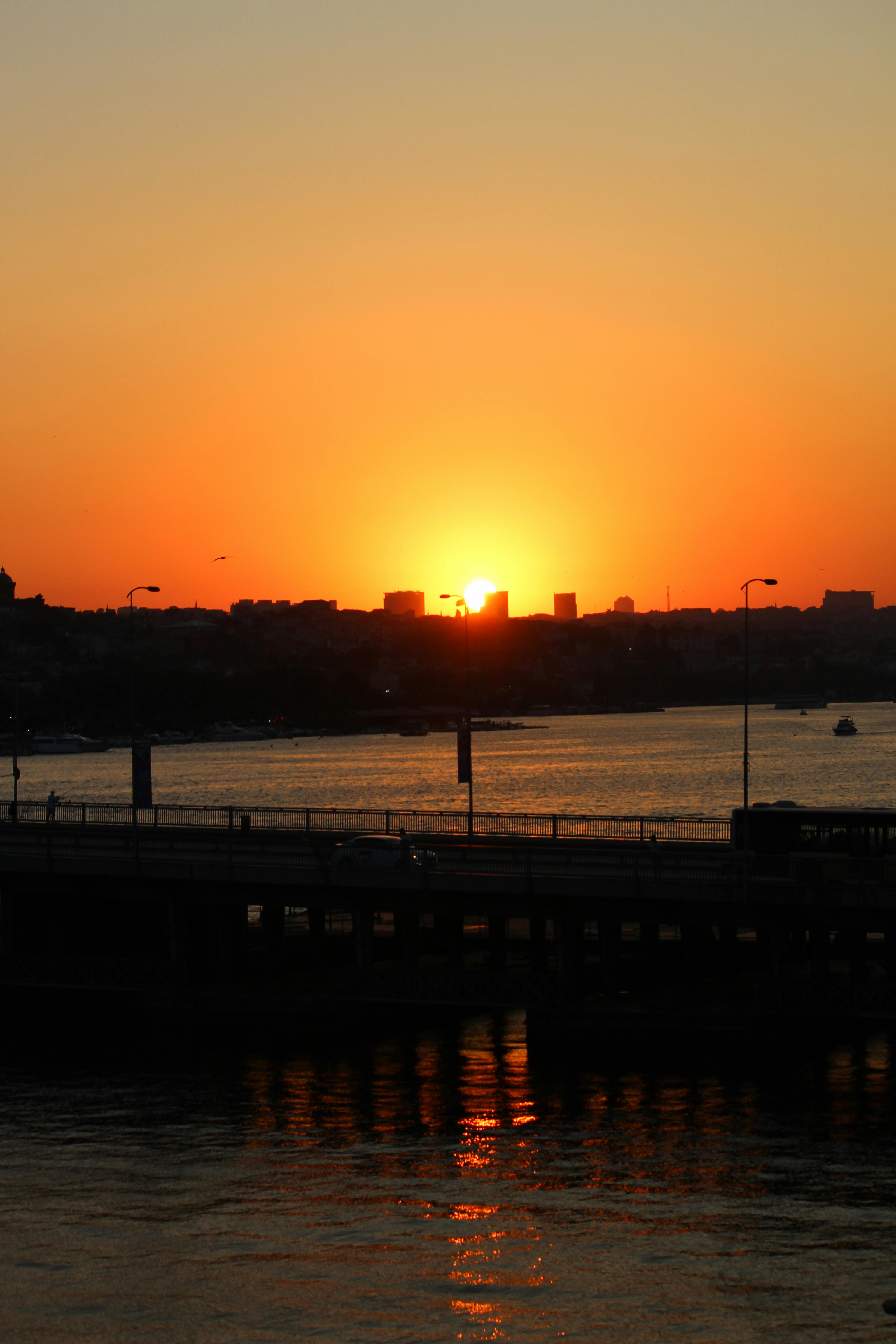 A sunset over a body of water with a bridge · Free Stock Photo