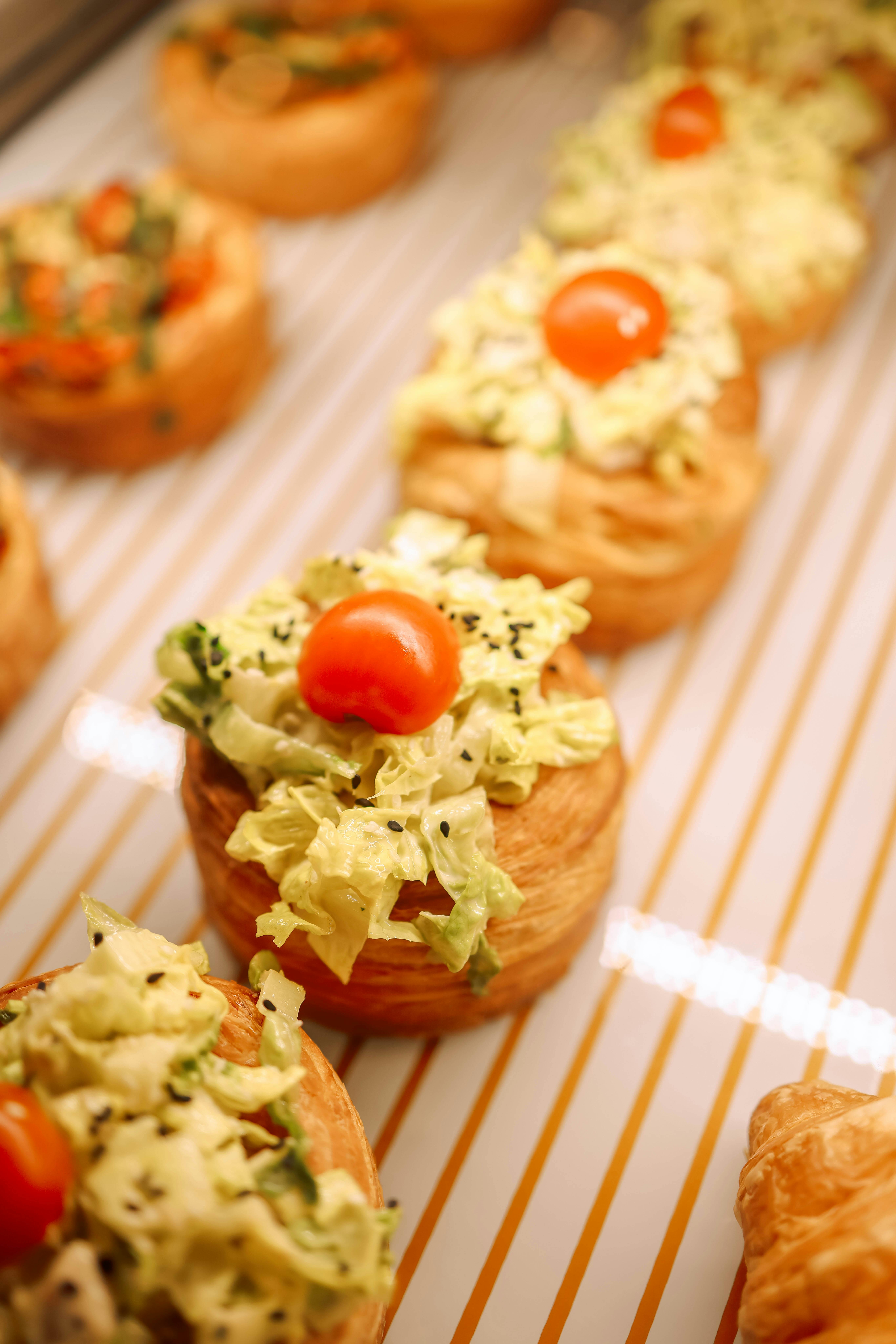Row of Pastries Topped with Lettuce and Tomatoes · Free Stock Photo